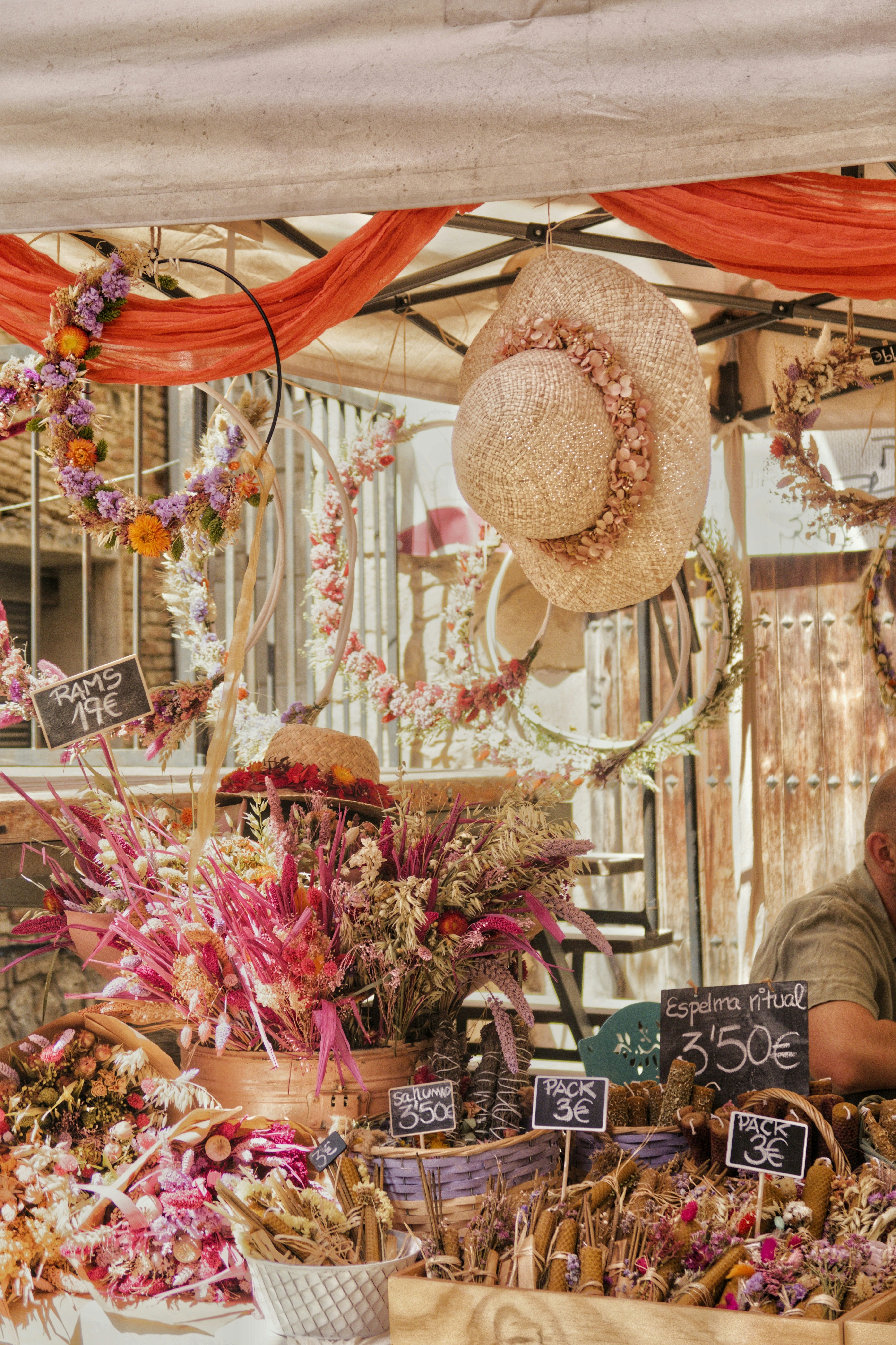 Straw hats and dried flowers at an outdoor market.