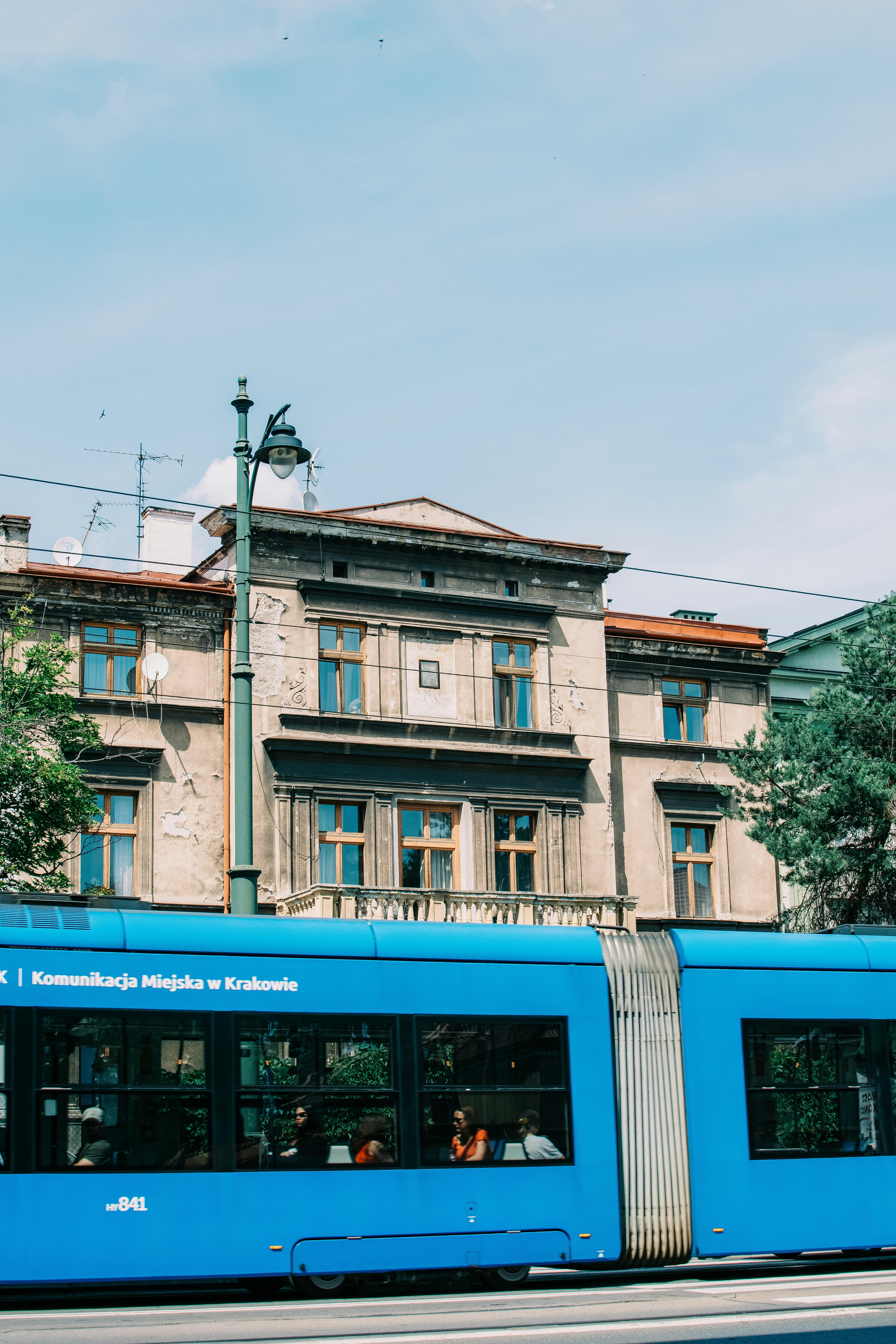 A blue tram passes by old buildings.