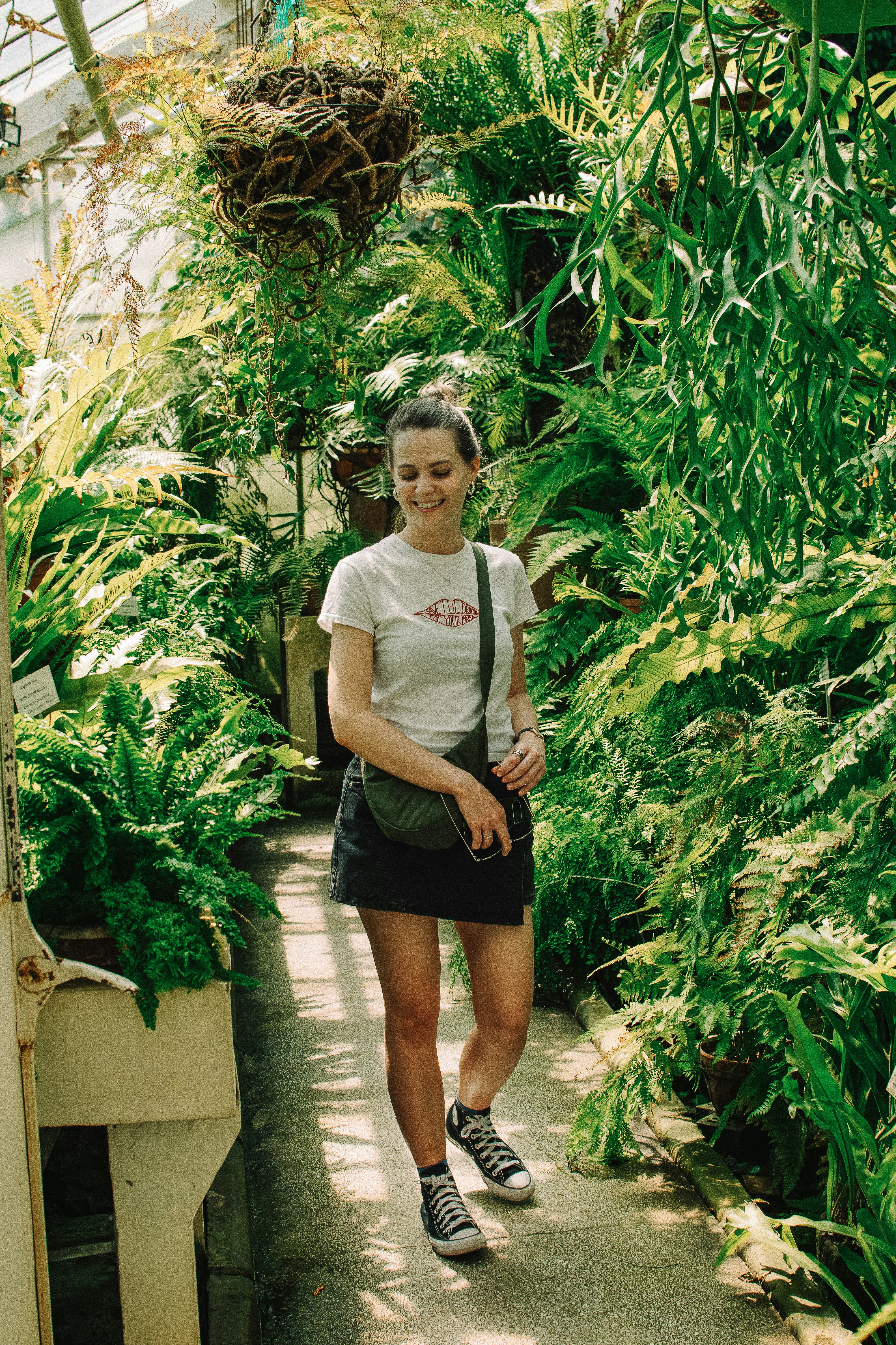 Woman walking through a lush green greenhouse