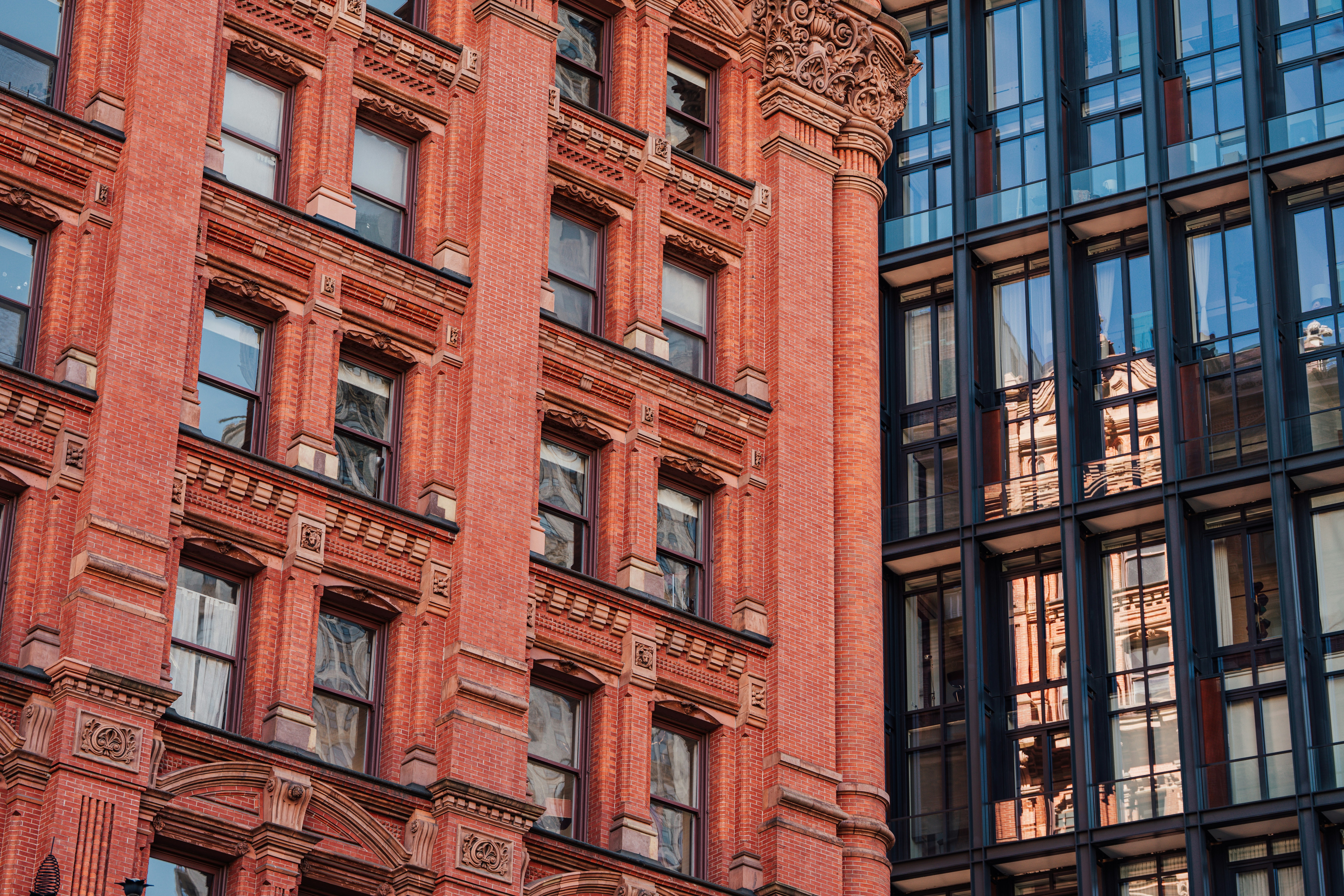 Brick facade of a historic building juxtaposed with a modern glass structure, reflecting urban architectural evolution.