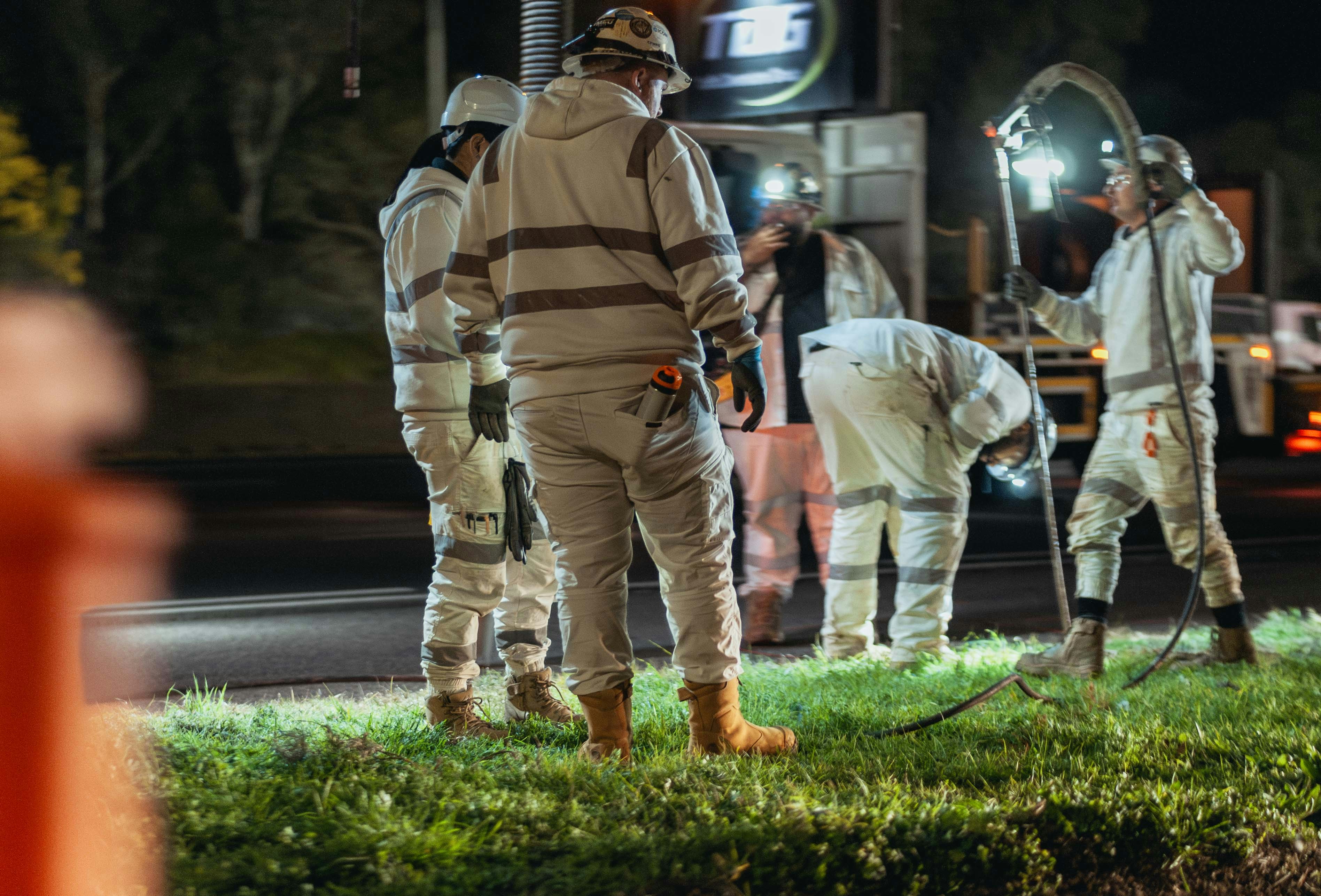 Construction workers in reflective gear working at night.