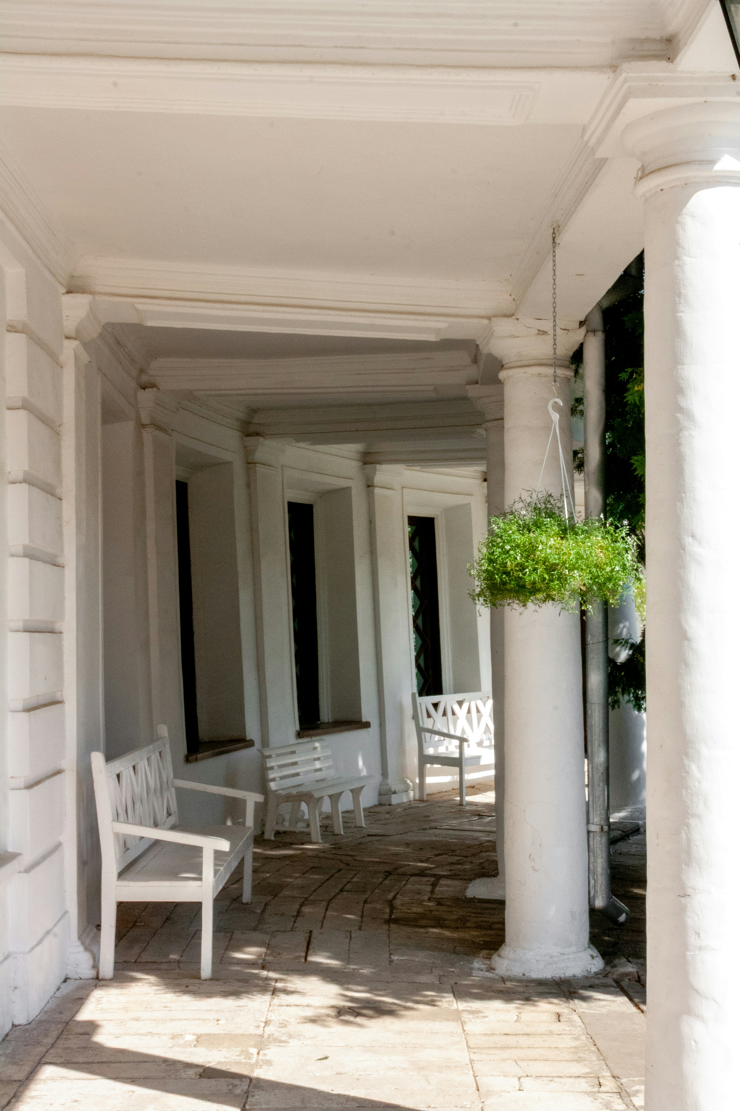 White porch with benches and hanging plants