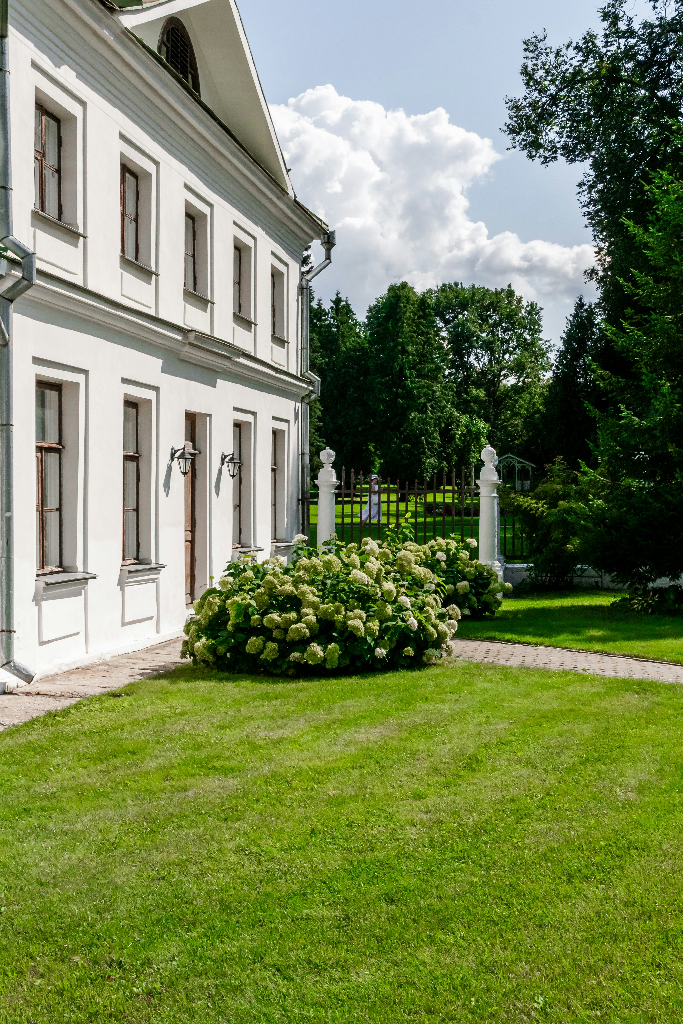 White building with green lawn and lush bushes