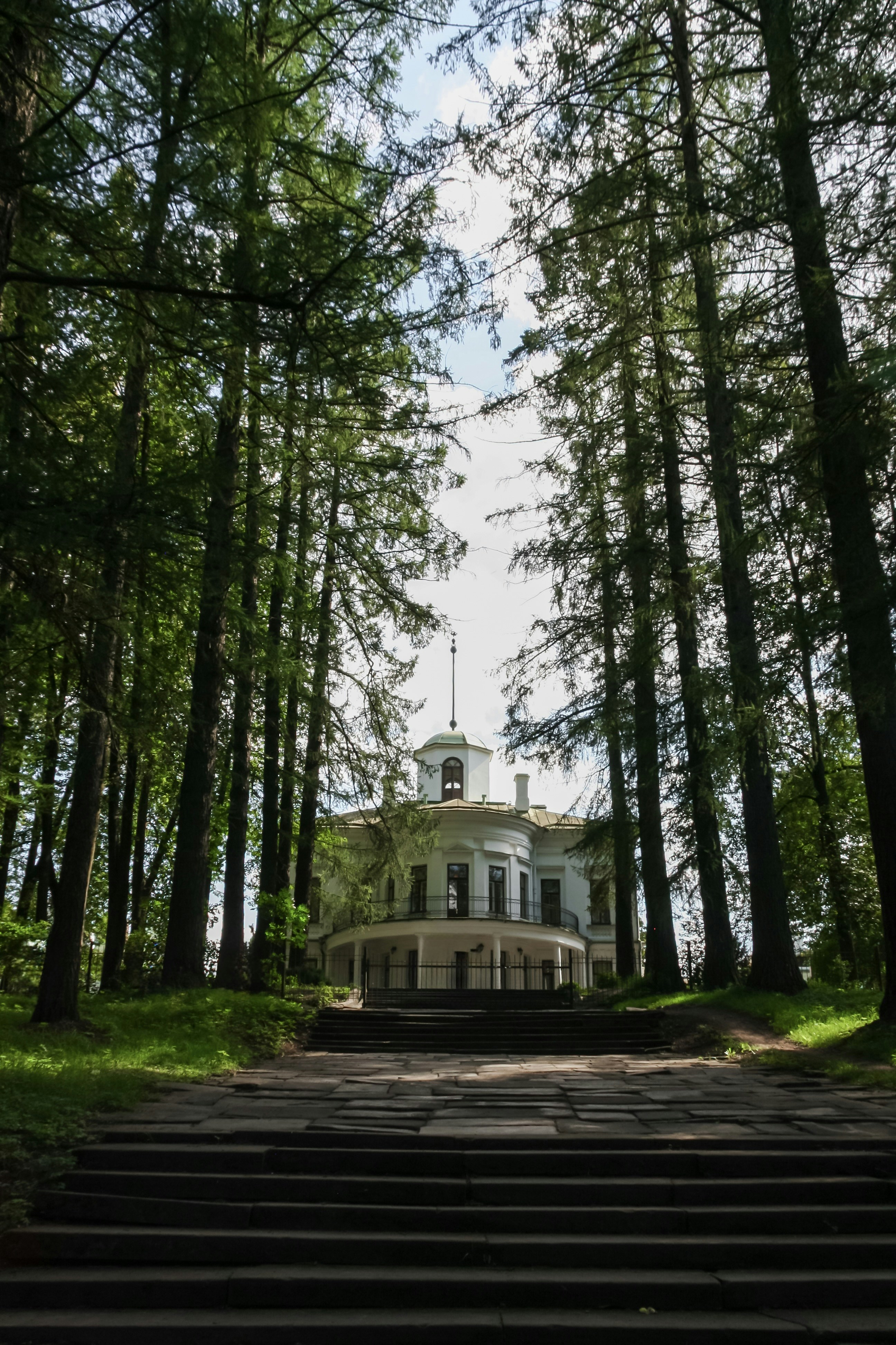 White building with a circular porch surrounded by trees
