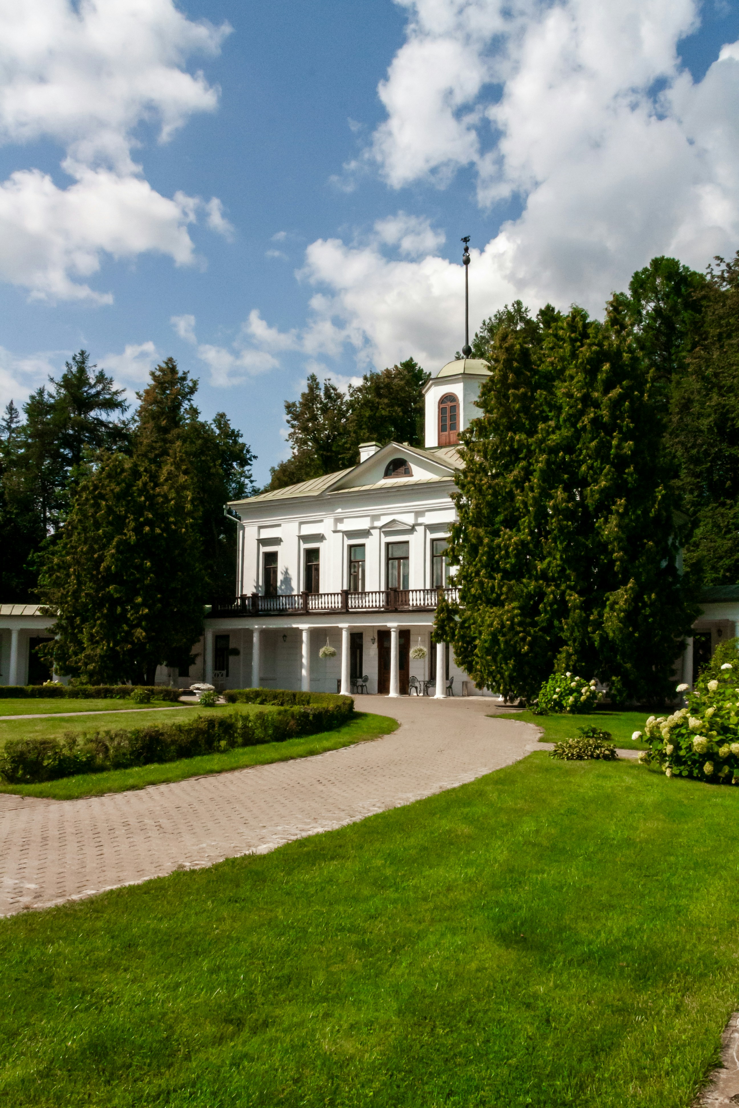 White manor house surrounded by lush green trees and gardens