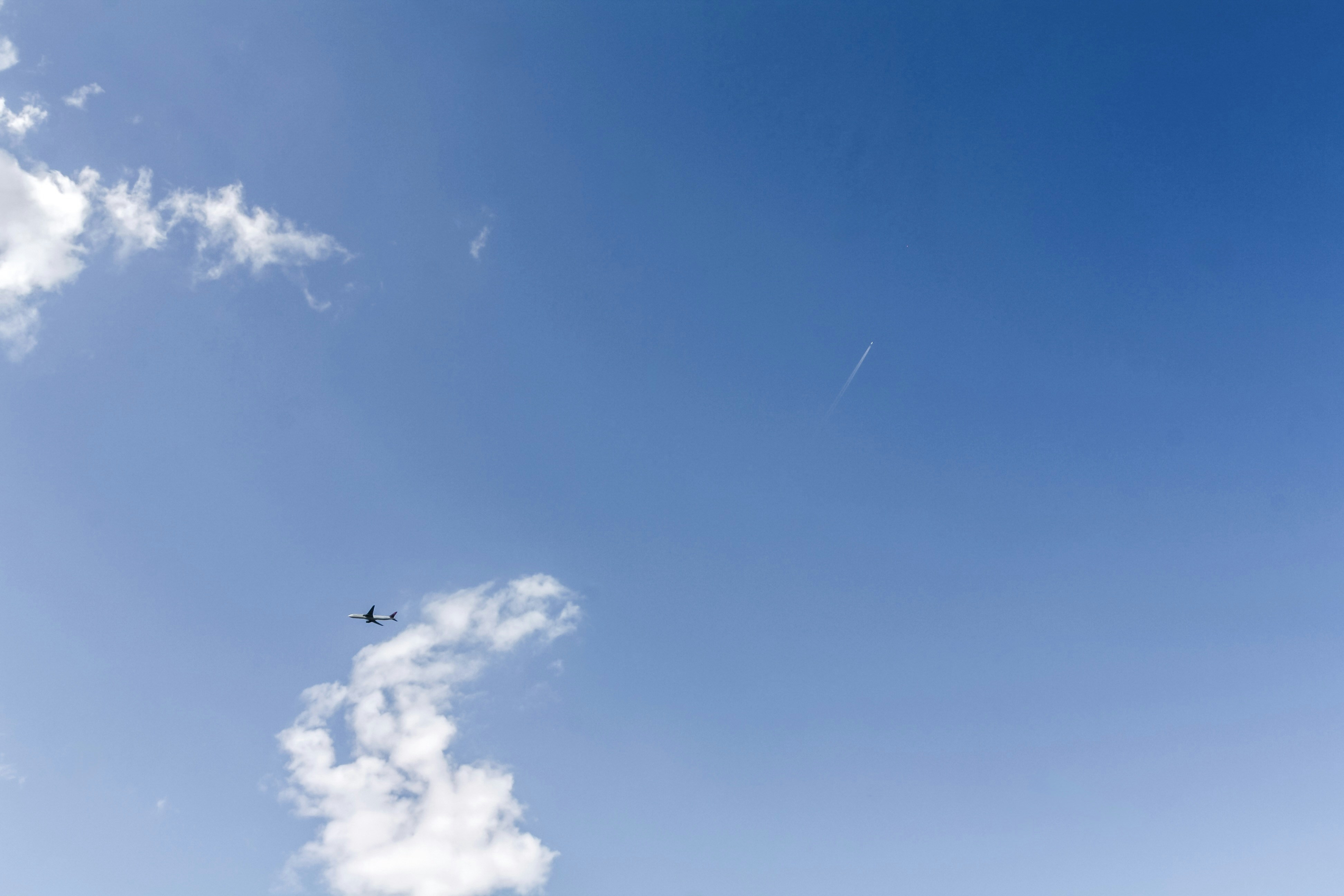 Blue sky with scattered white clouds and airplane.