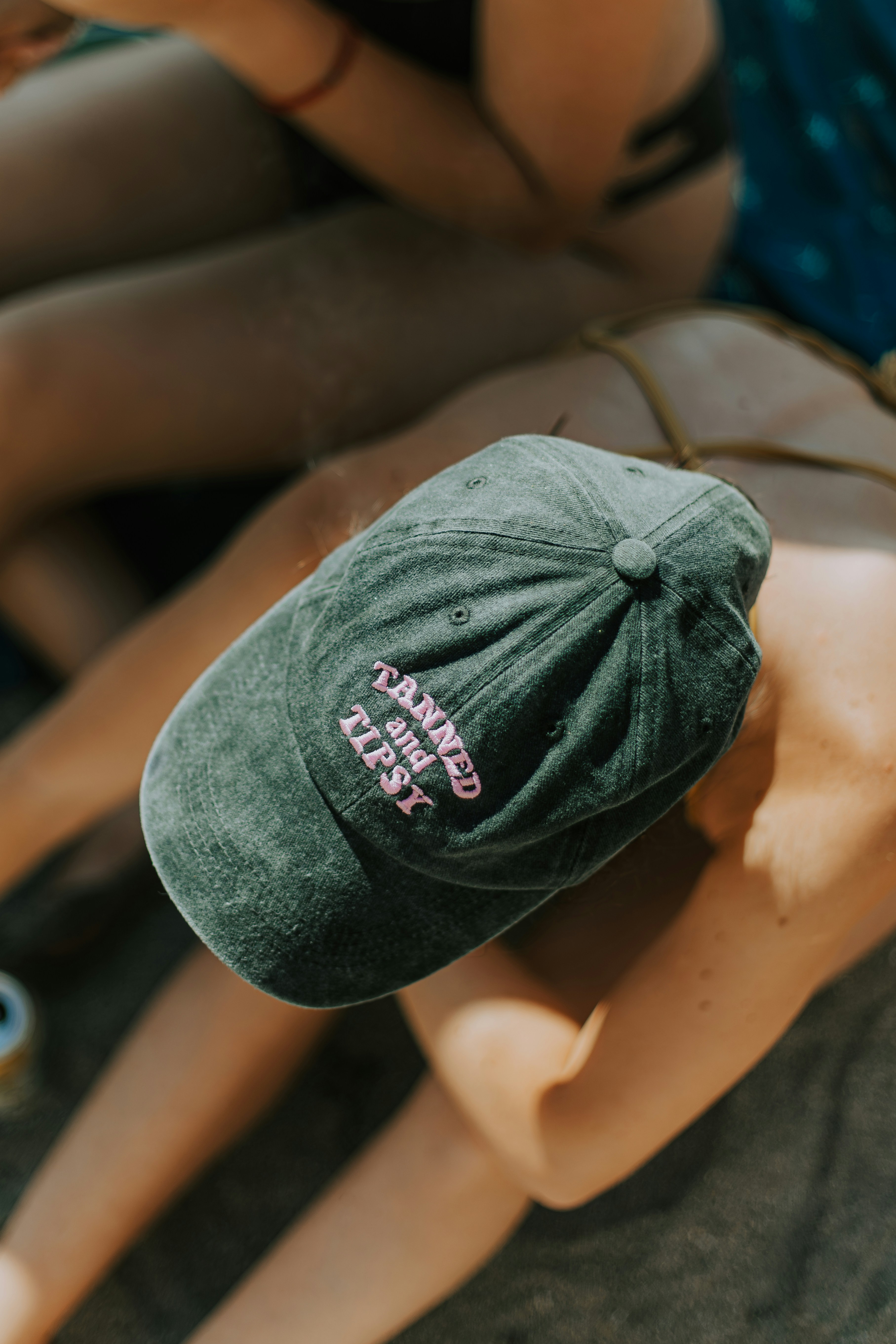 A dark green baseball cap with pink text.