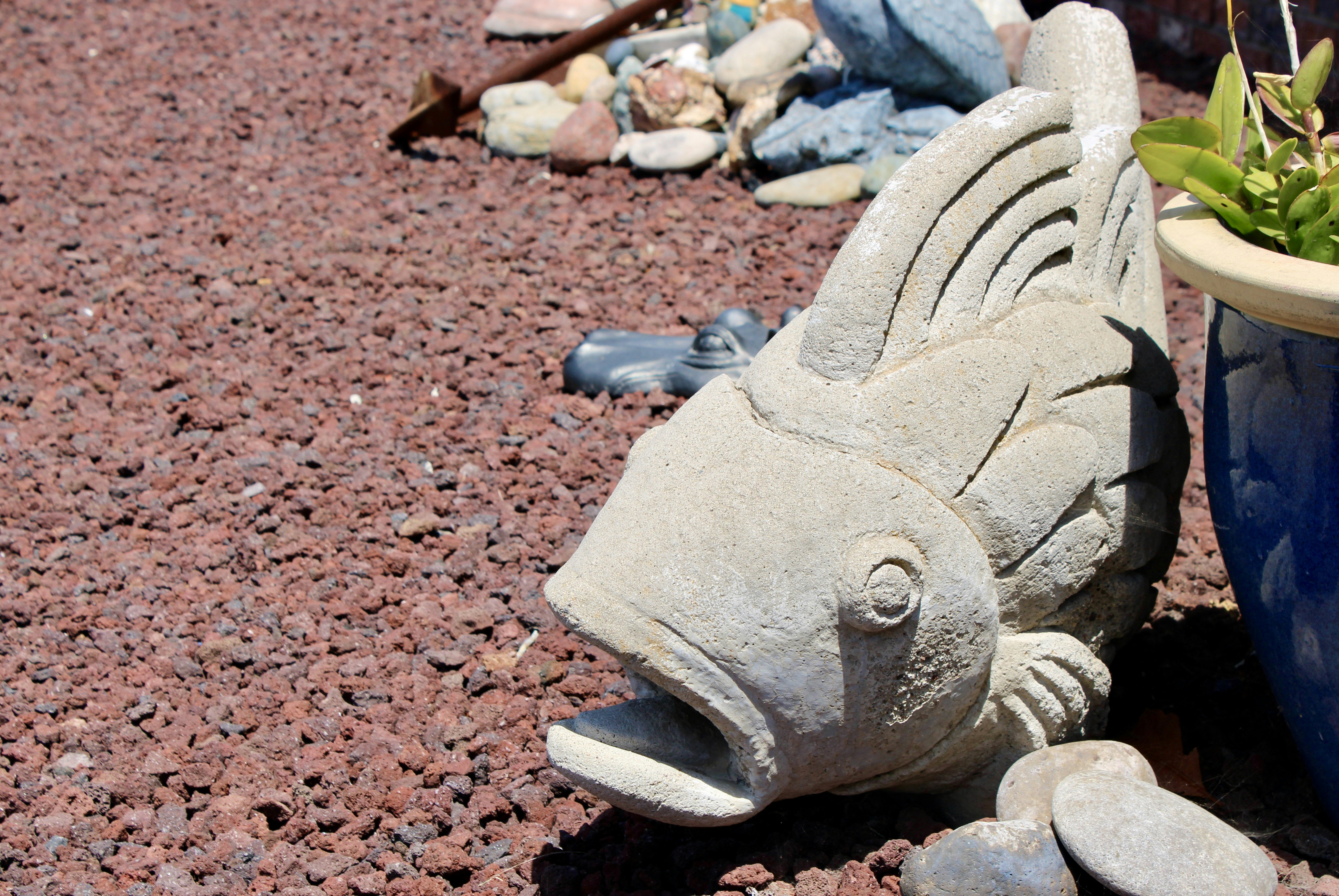 Stone fish sculpture in a garden setting