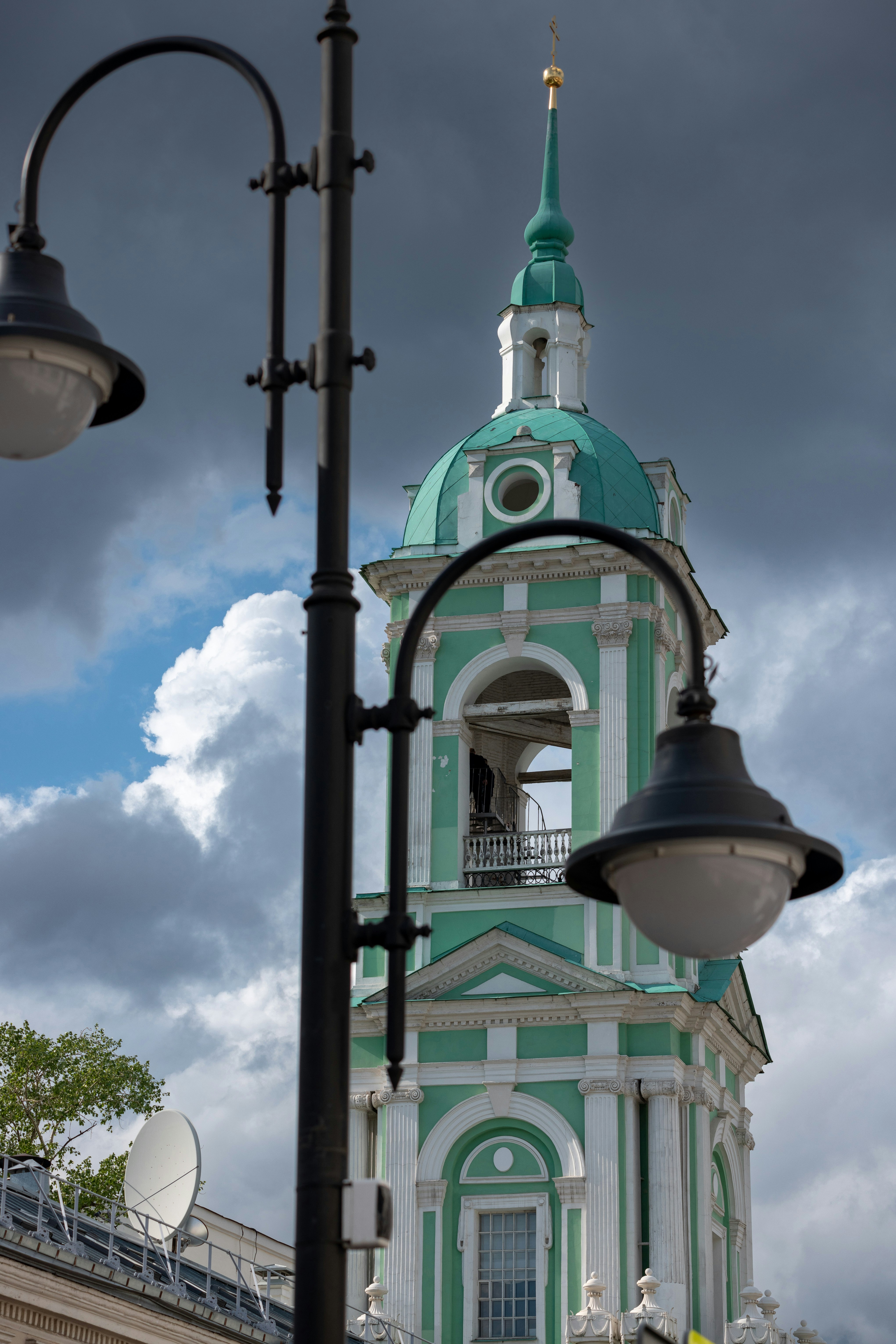 Green and white church tower with street lamps