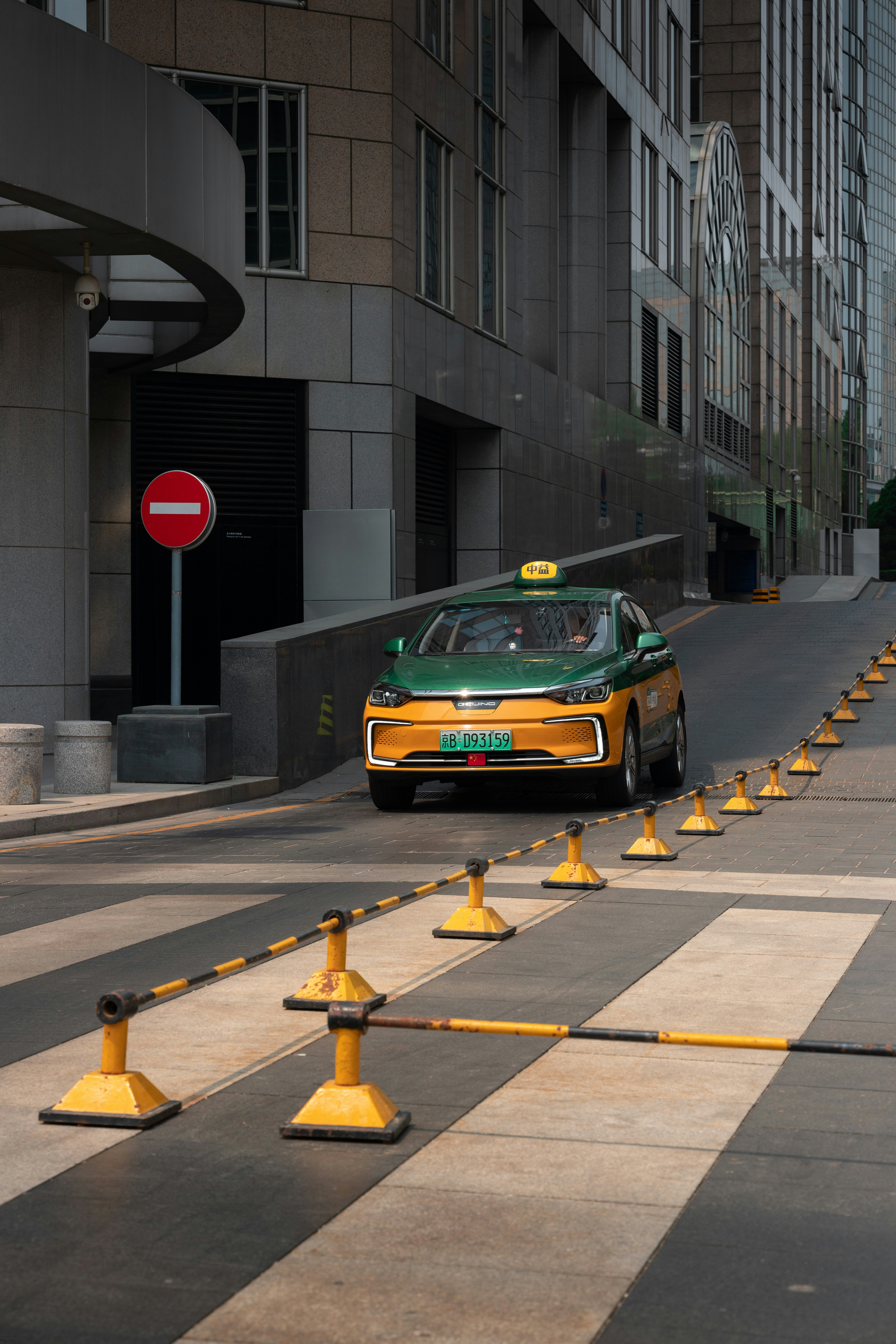 A yellow and green taxi drives up a ramp.