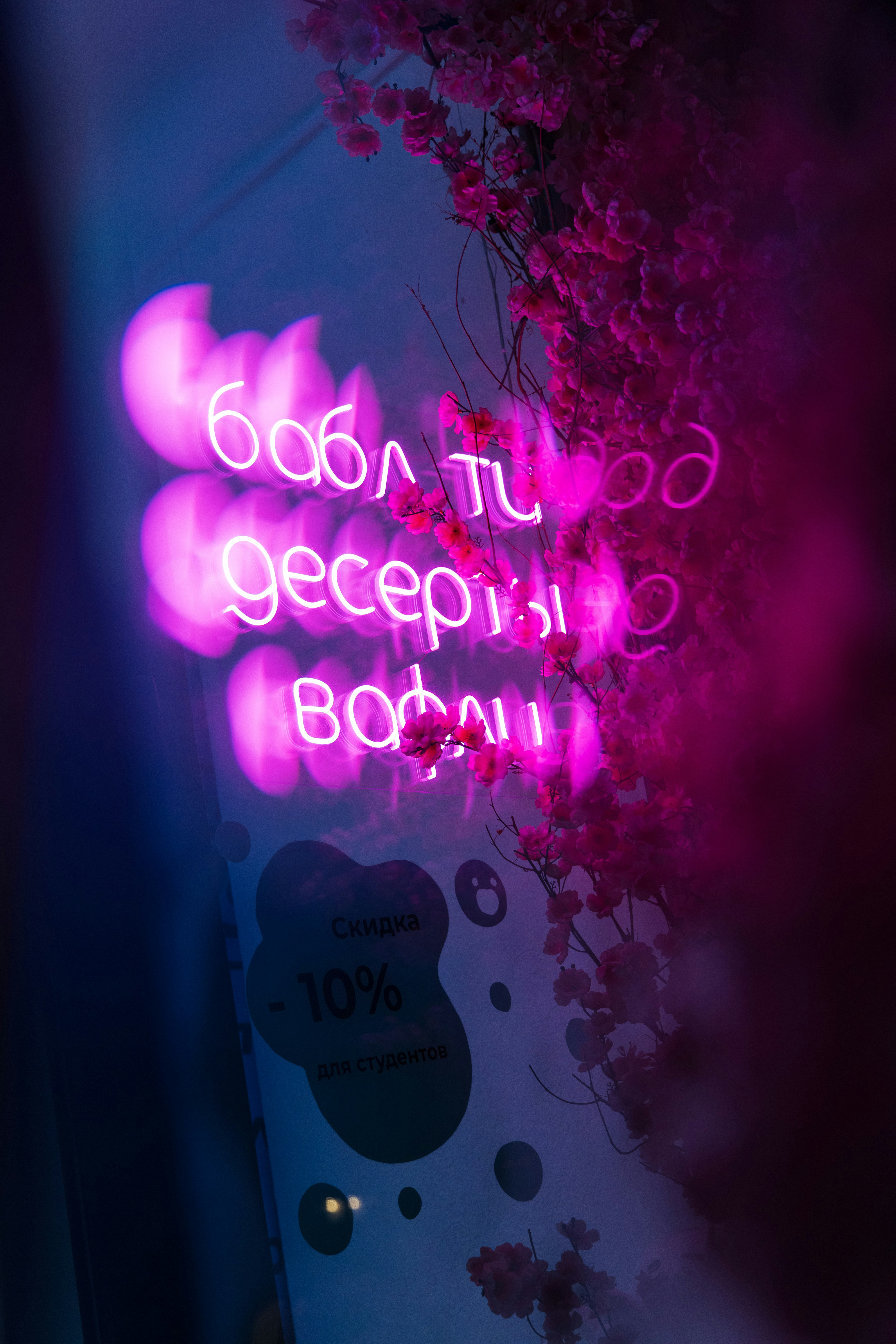 Neon sign with pink flowers and bokeh effect