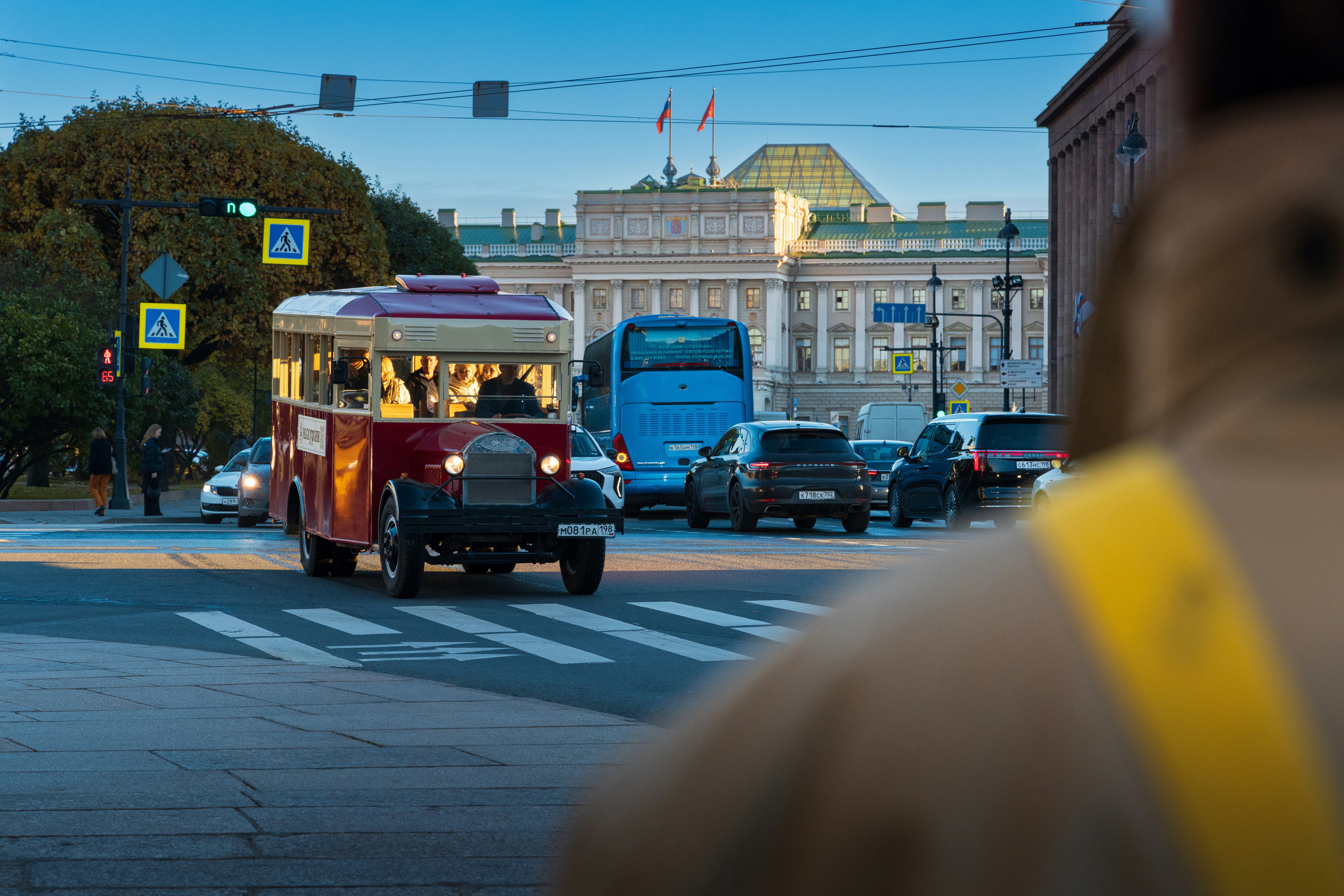 Vintage bus driving through city street with buildings.