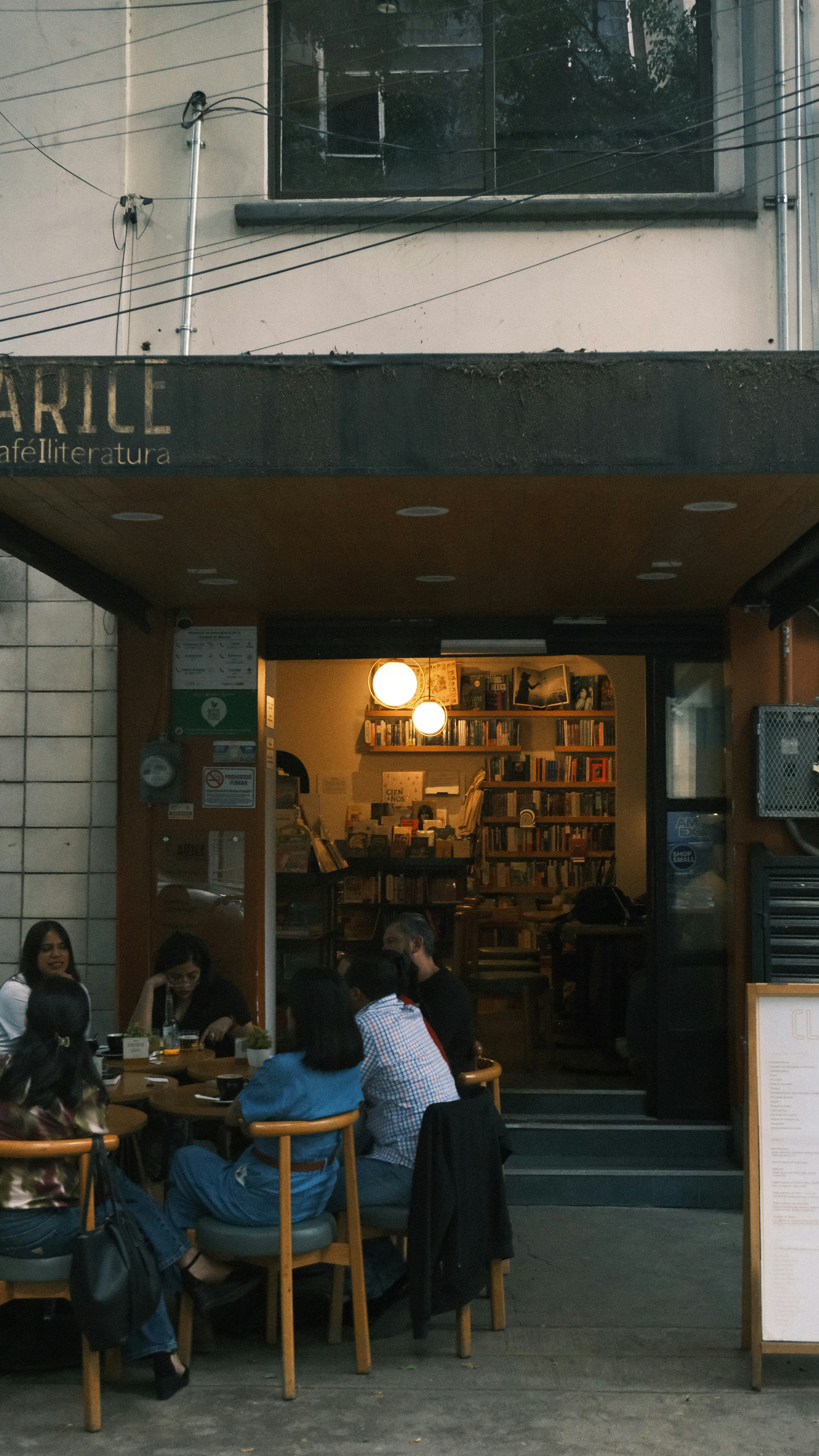 People sitting at tables outside a bookstore cafe