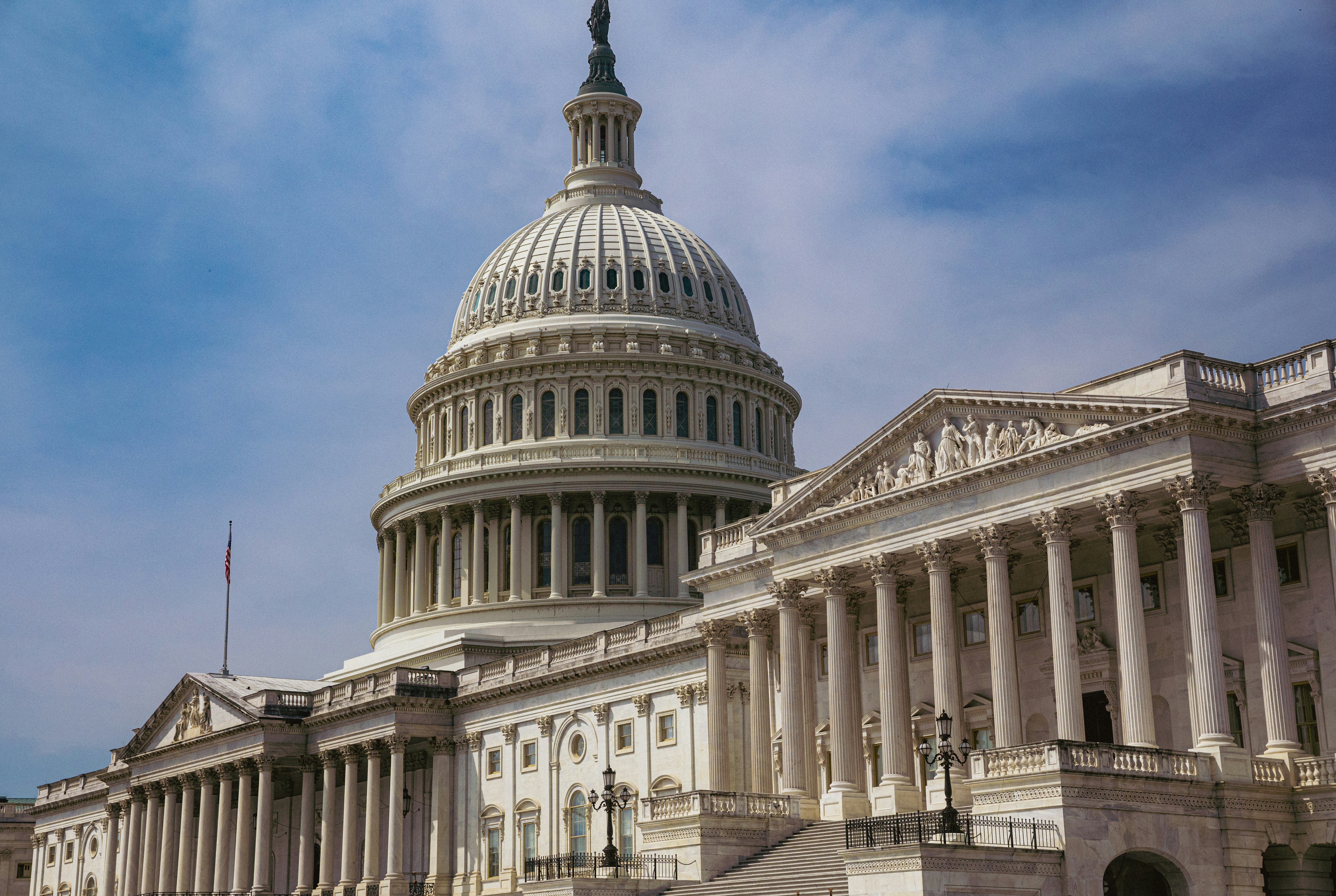 The United States Capitol building showcases its iconic dome and neoclassical architecture under a clear blue sky.