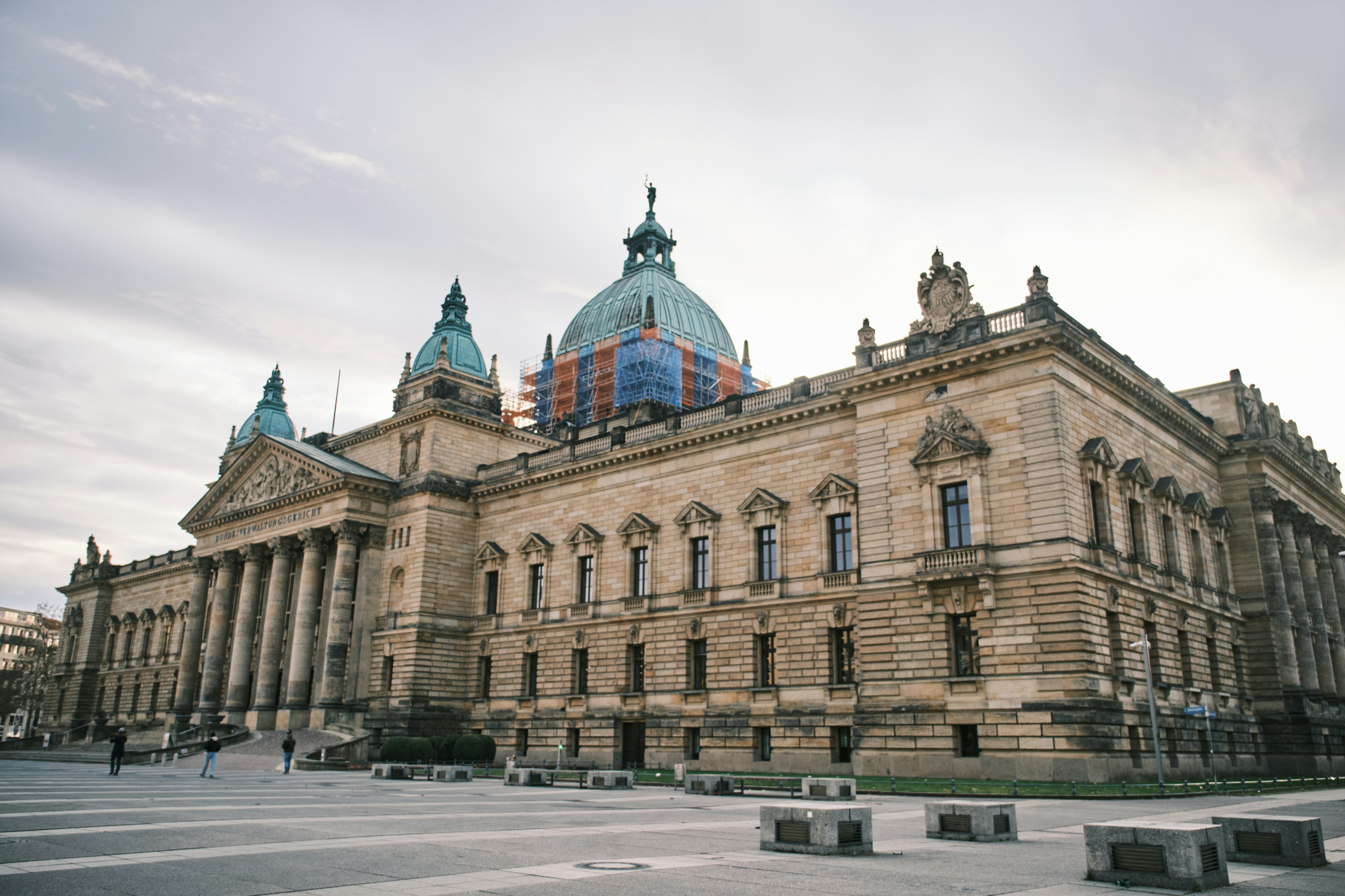 Historic building featuring grand columns and a prominent dome, partially obscured by scaffolding. The structure showcases intricate architectural details.