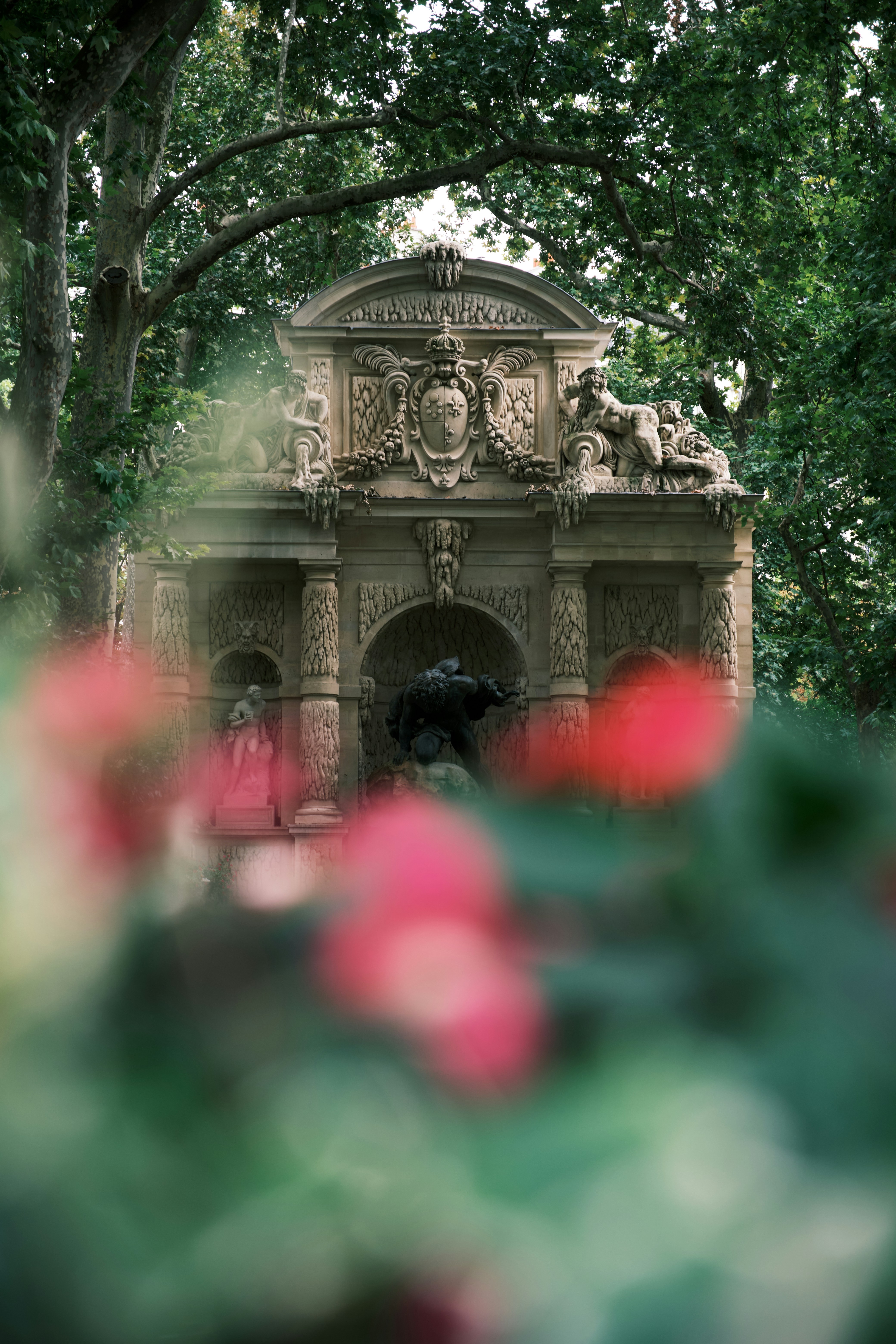 Ornate fountain with lush greenery and blurred flowers