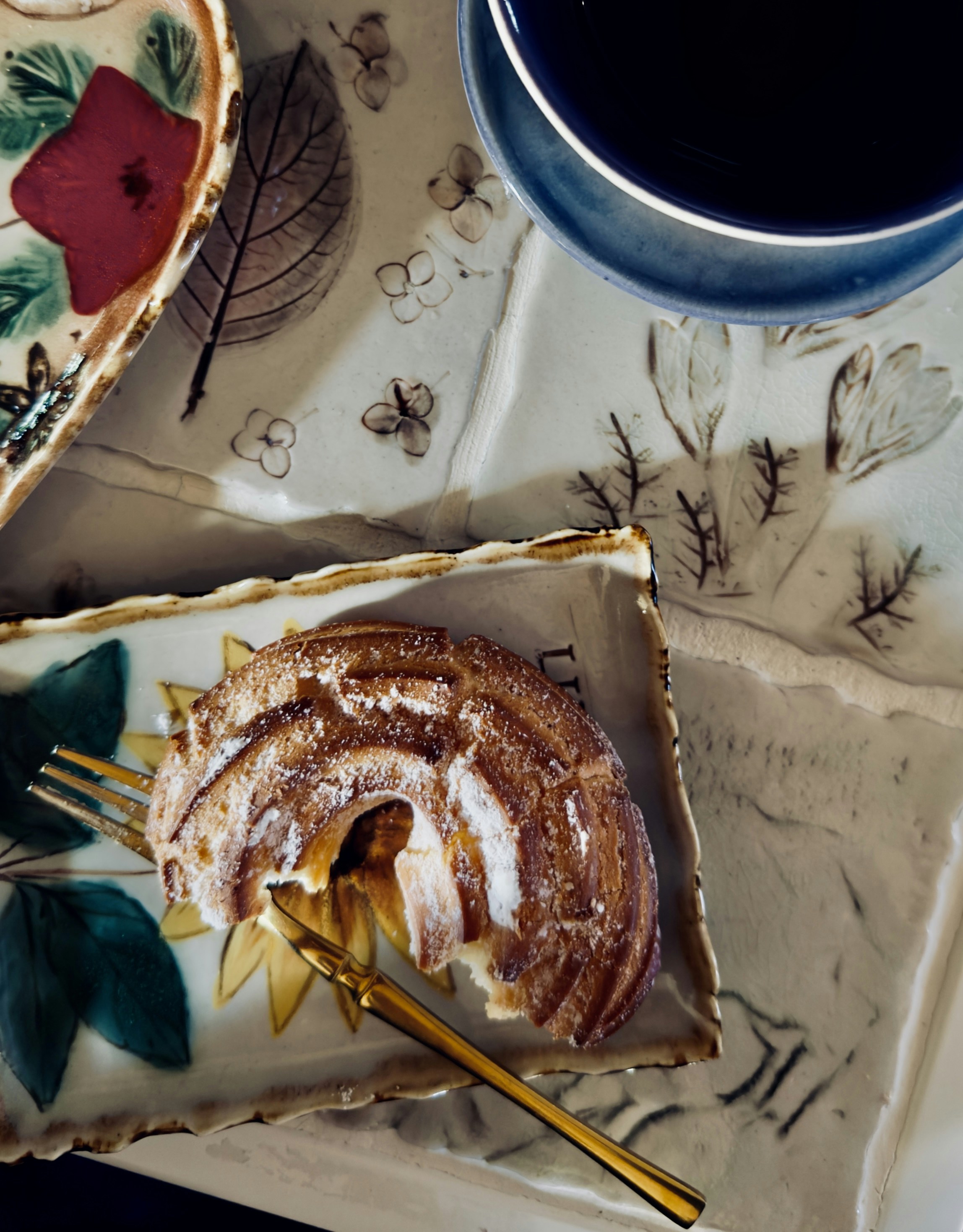 Pastry on a decorative plate with a cup of coffee.