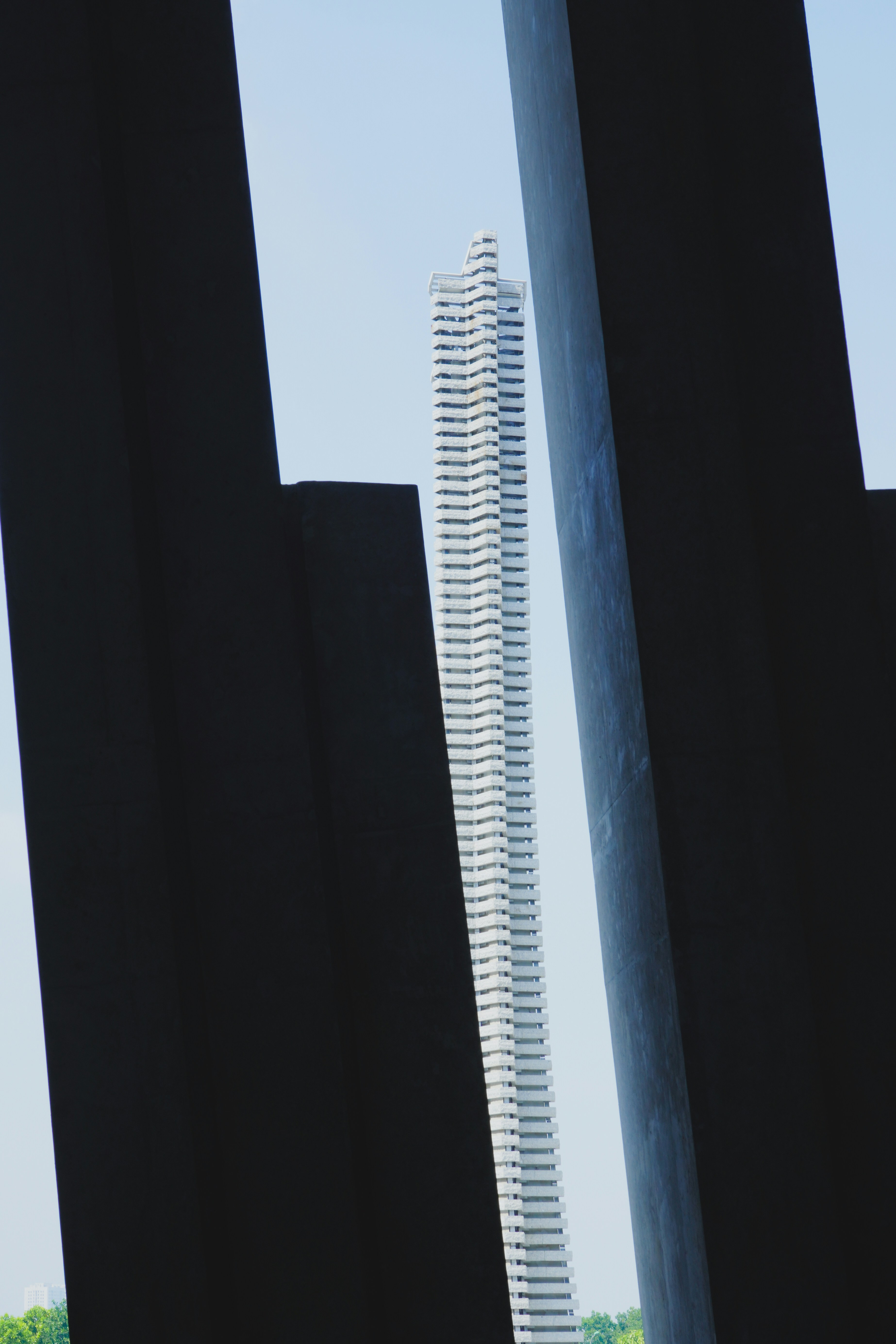 Tall white skyscraper framed by dark structures
