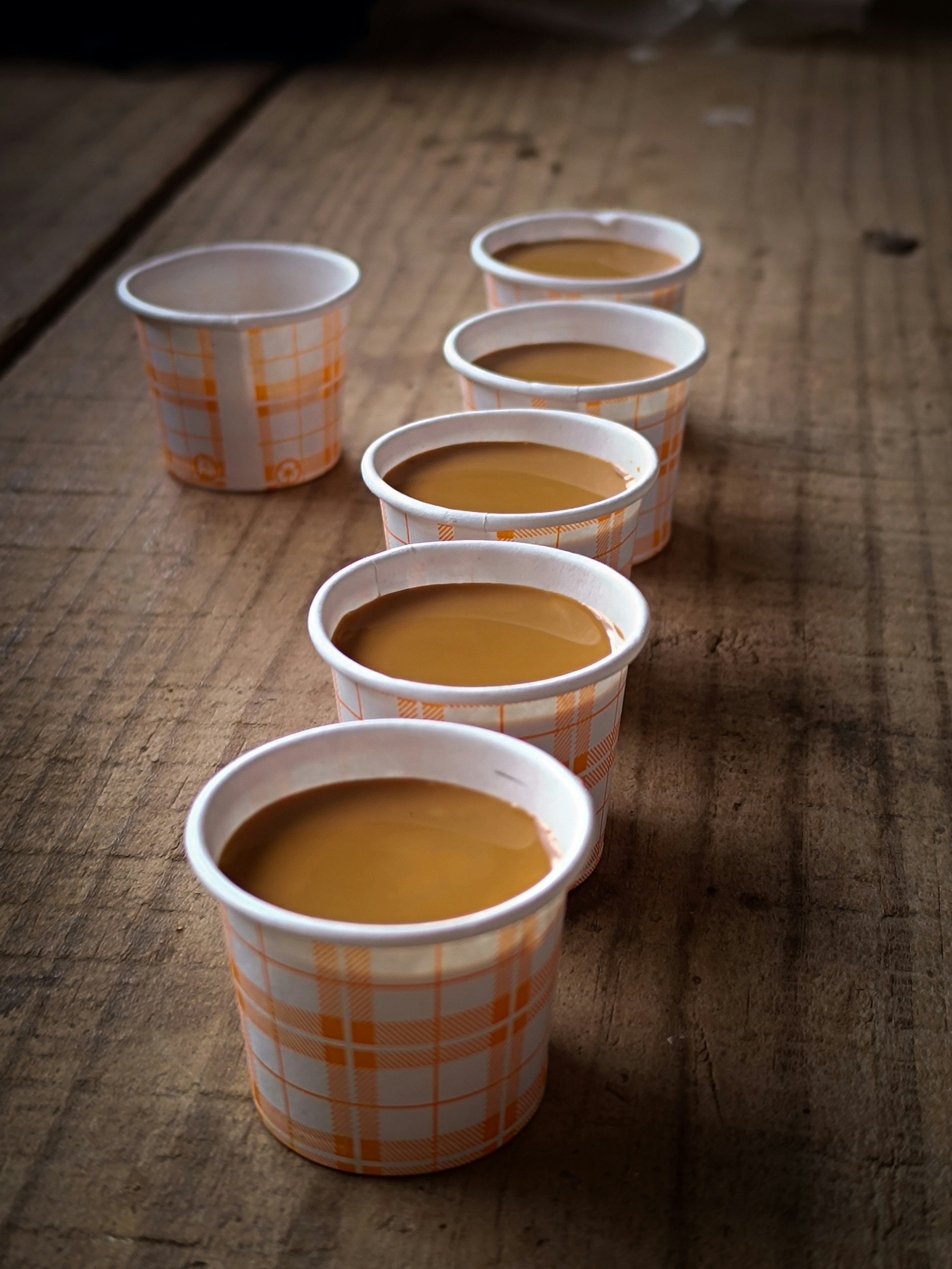 Tea is a popular beverage that is usually made by Accepted steeping the leaves of the Camellia sinensis plant in hot water. It is widely consumed around the world and is available in a variety of flavors.In Ayurveda, tea is also used as a medicine, especially when spices like basil, ginger, cinnamon and cloves are added to it. It provides energy and can be helpful in calming kapha-pitta. | Five cups of tea lined up on a wooden surface.