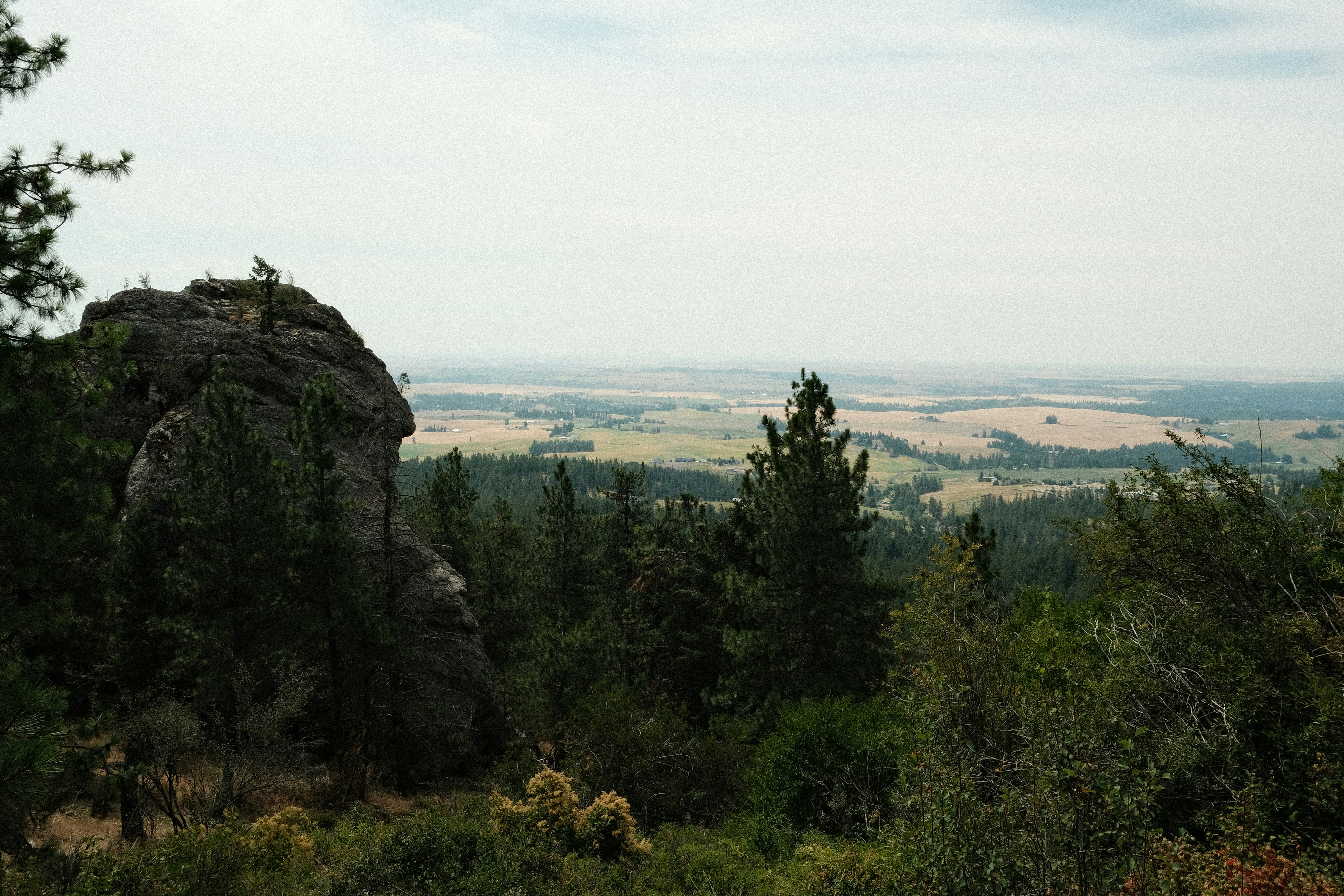 Rocky outcrop overlooking a vast landscape under a cloudy sky