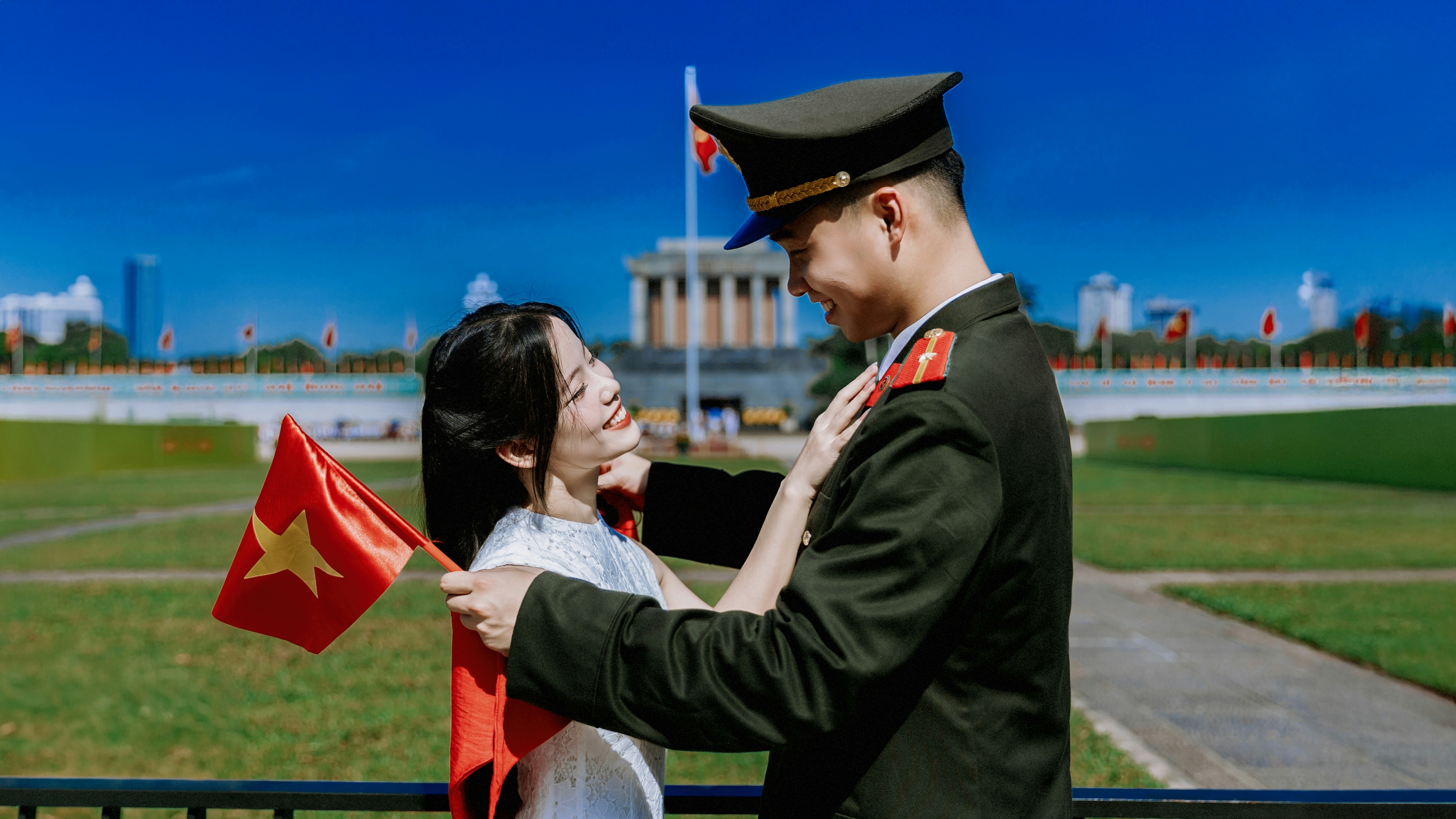 Couple embracing while holding a Vietnamese flag at a historic site, showcasing cultural pride and connection.