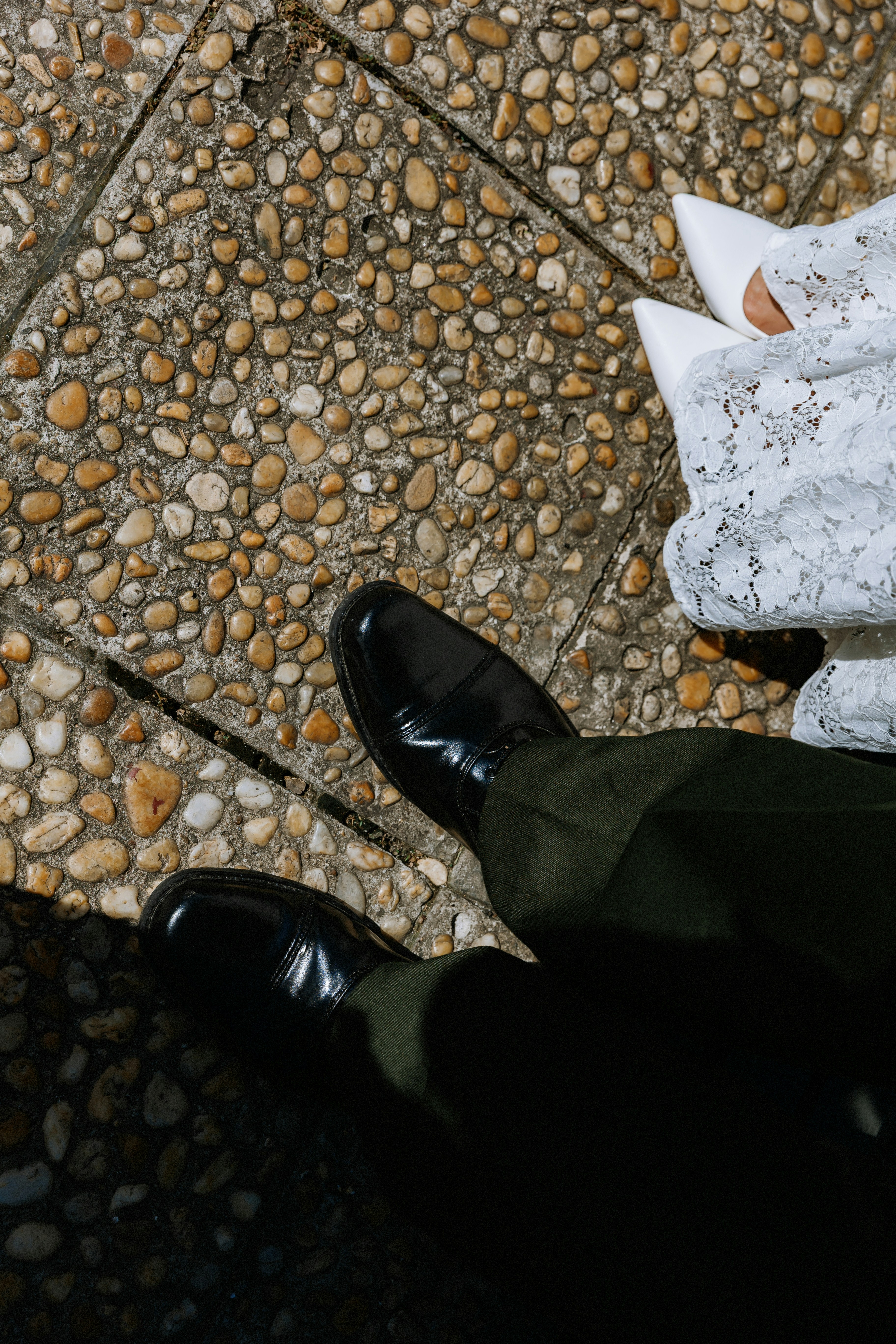 Couple portrait outdoors in Hanoi | Man's black shoes and woman's white heels on pavement