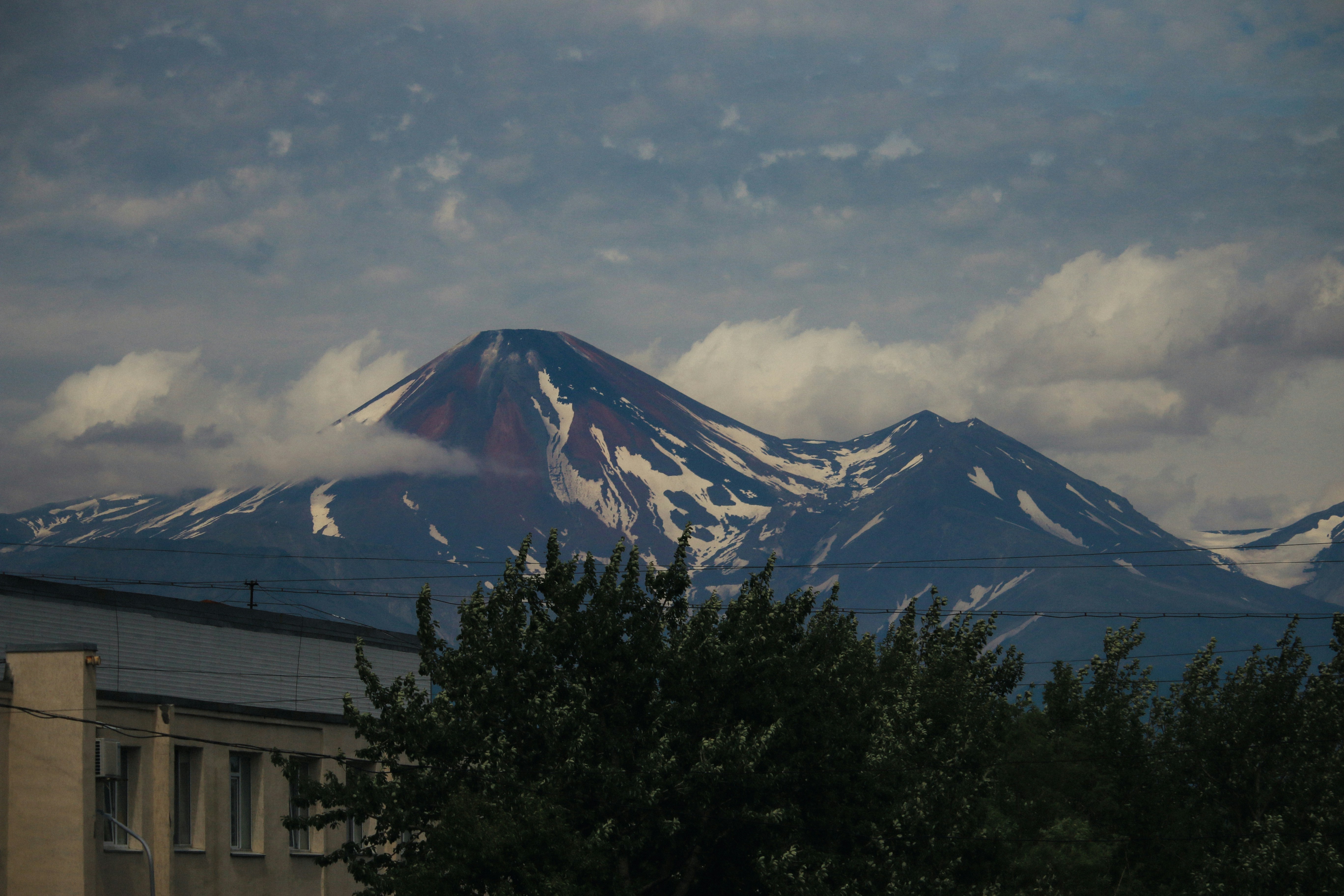 Snow-capped volcano peaks under cloudy skies