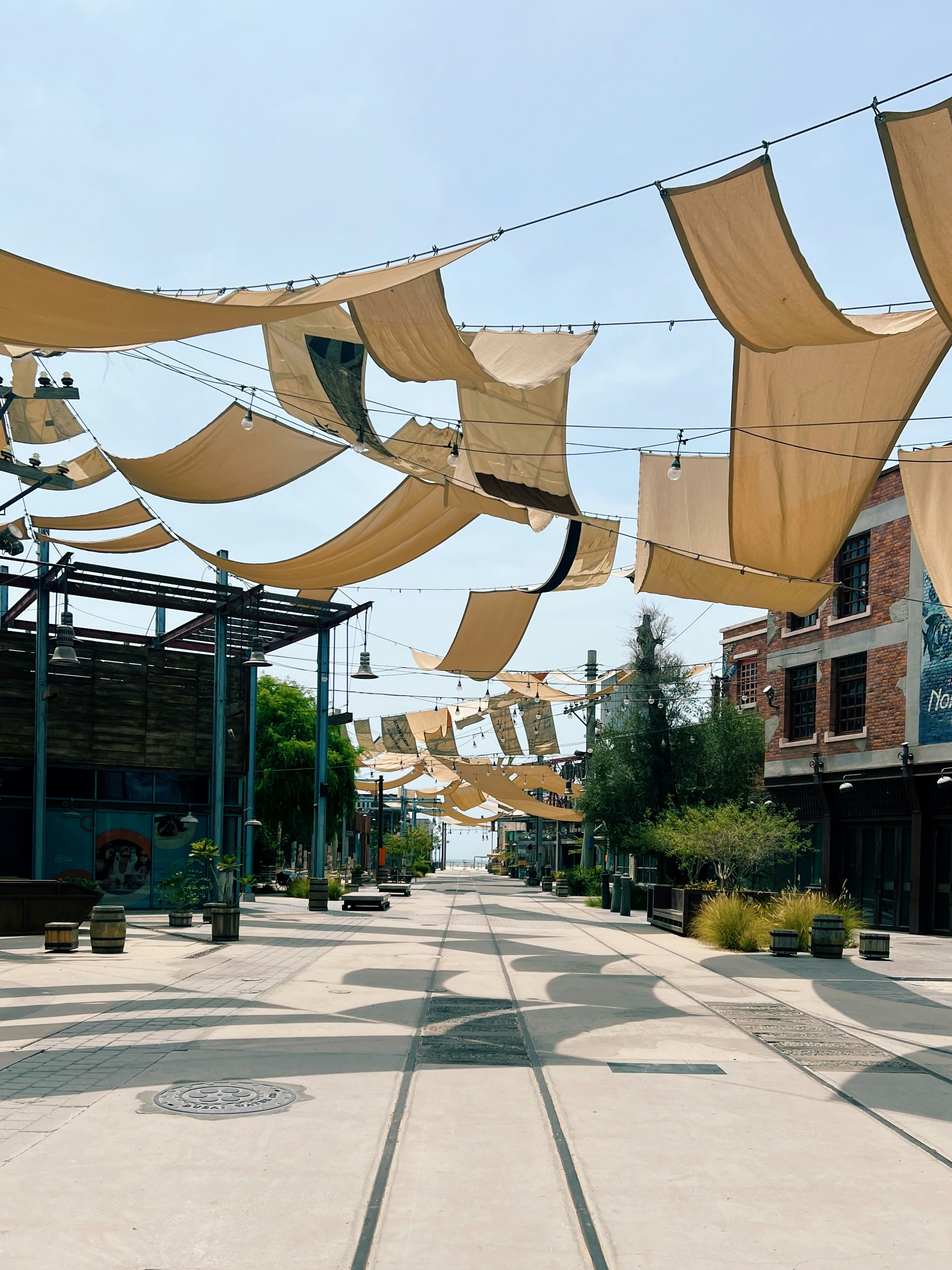 Street with fabric shades and buildings under clear sky