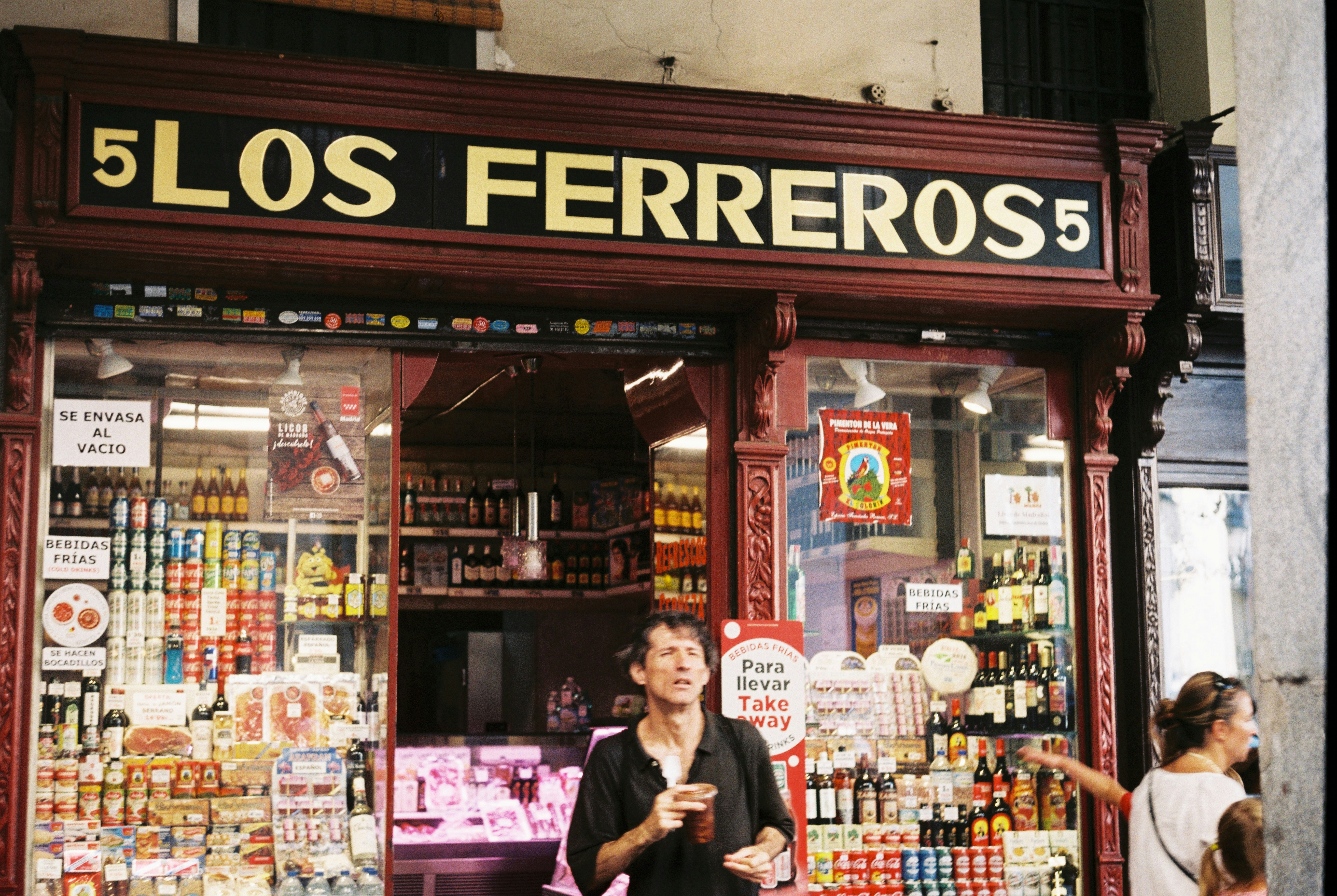 Local man exiting a deli store in Madrid | People in front of a busy grocery store