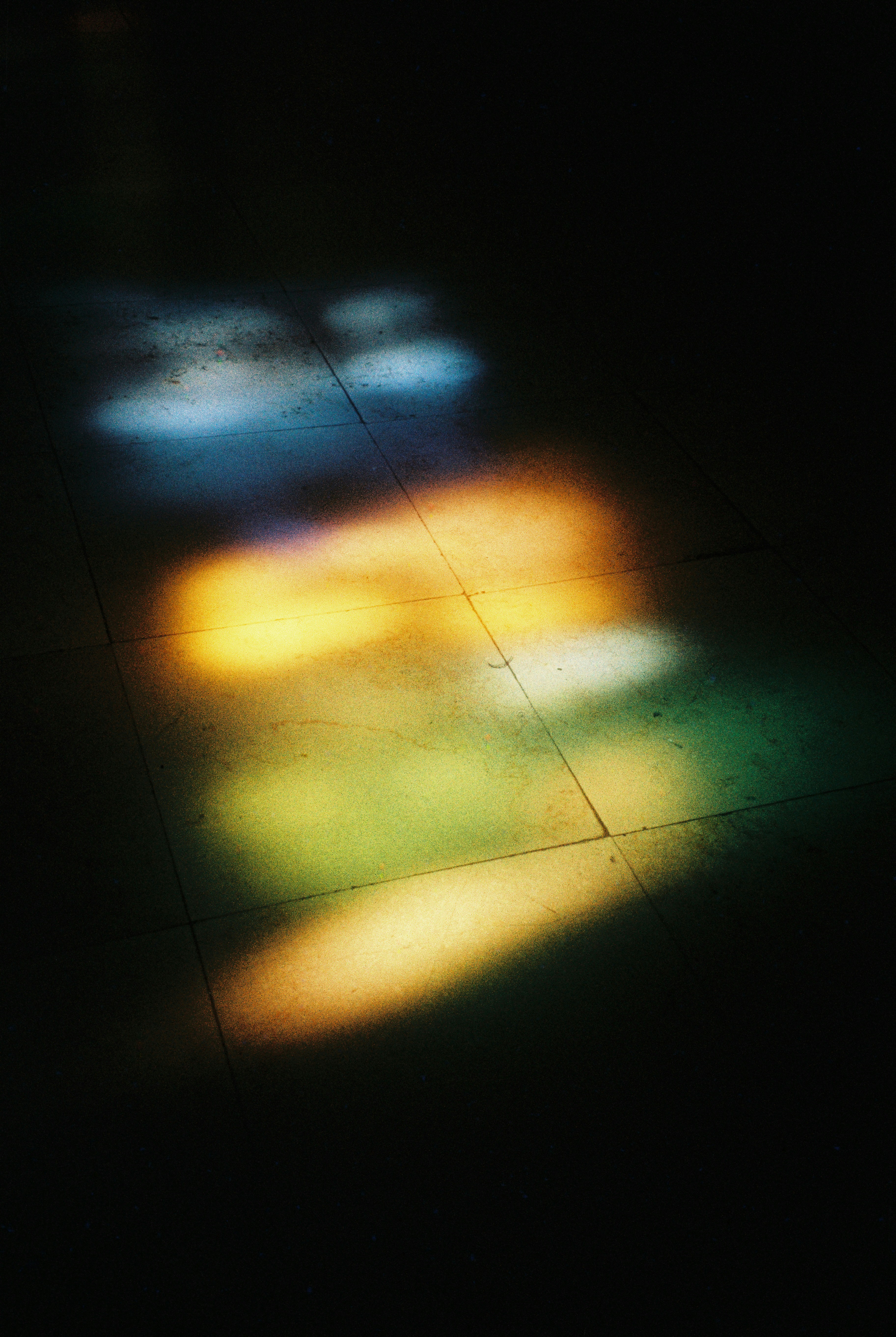 Shot on OptiColour 200 | Colorful light patterns on a dark tiled floor.