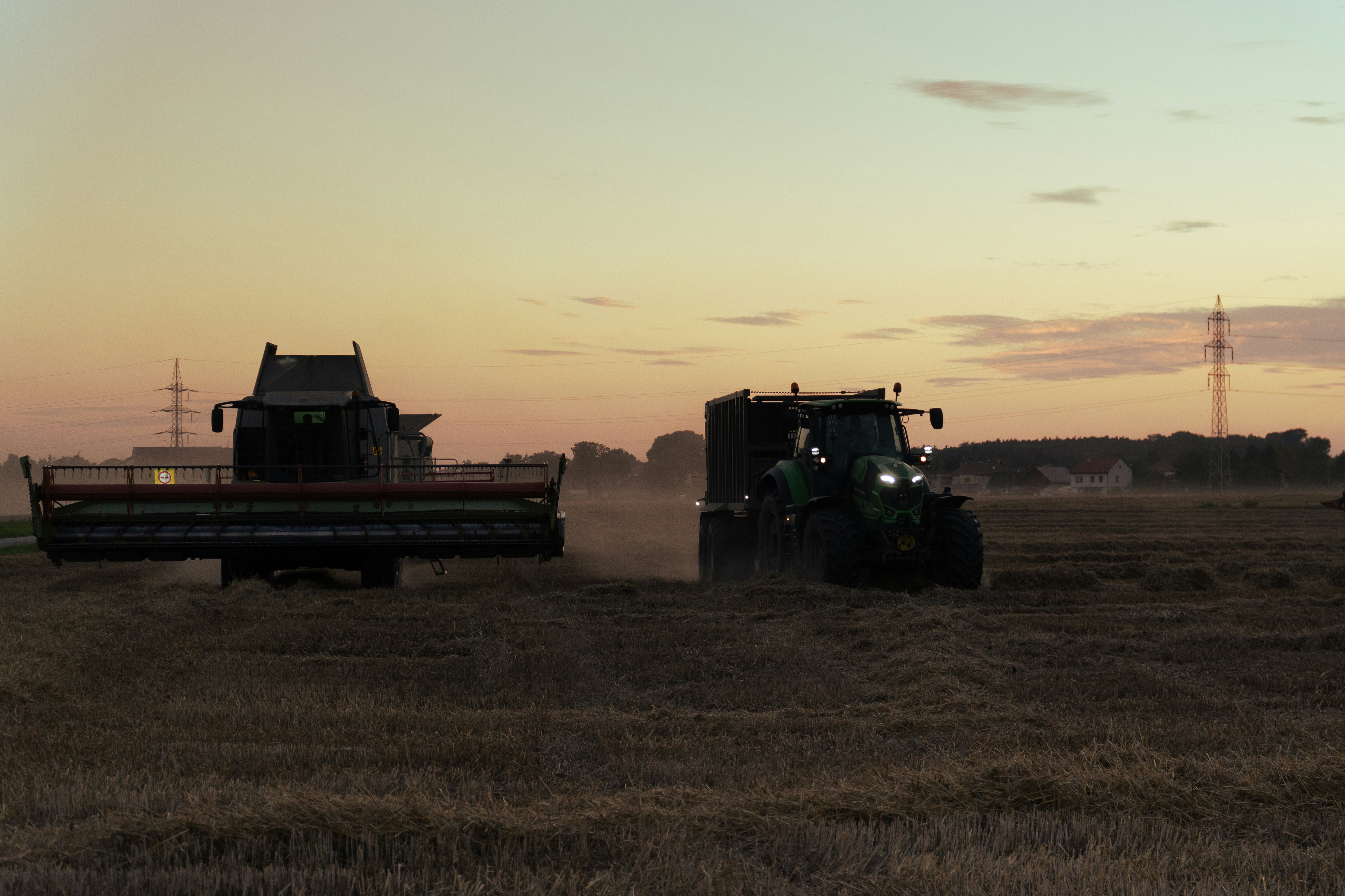 Excavators working on an open field, preparing the ground for construction | Combine harvester and tractor working in field at sunset