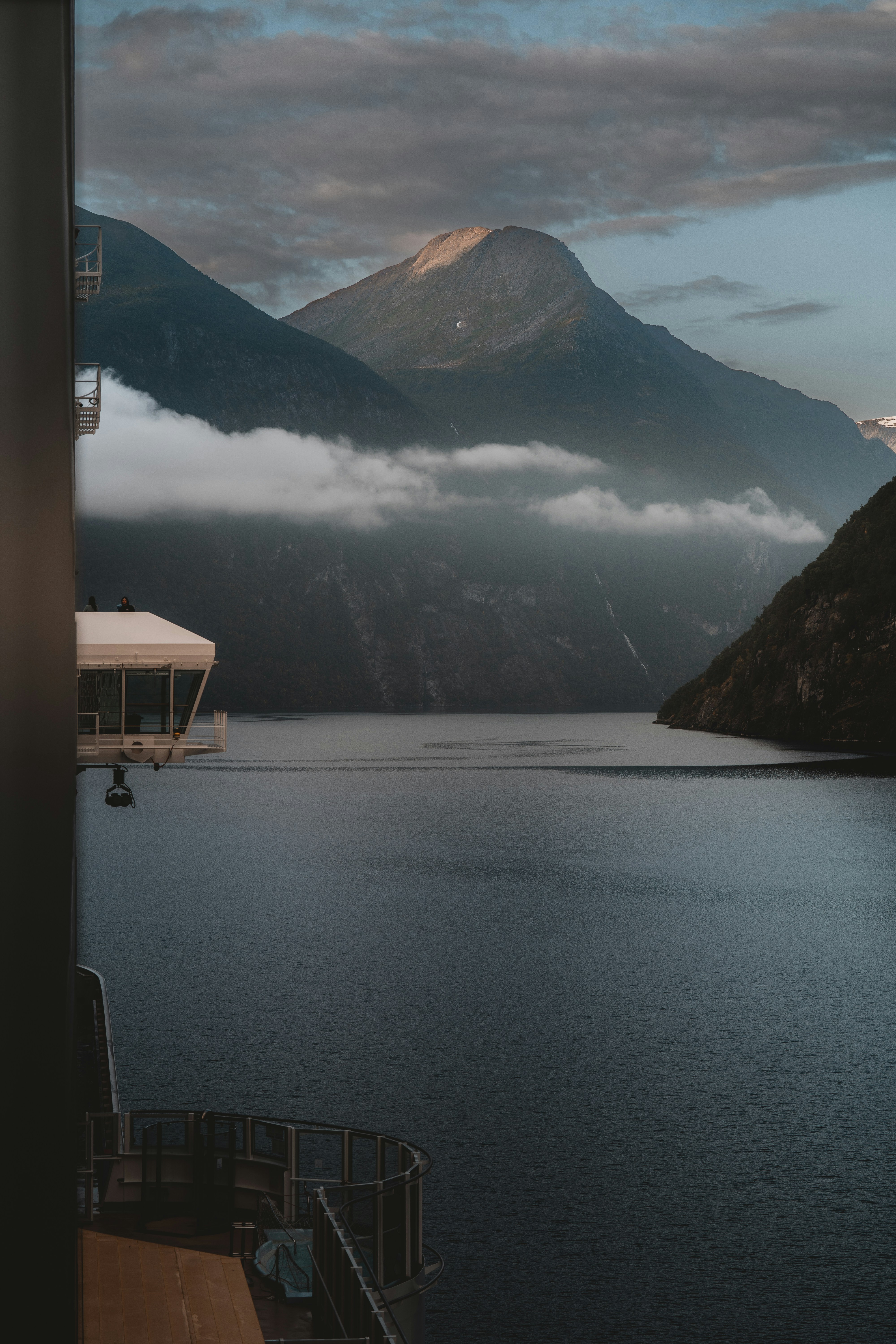 Calm water with misty mountains and a cruise ship balcony.