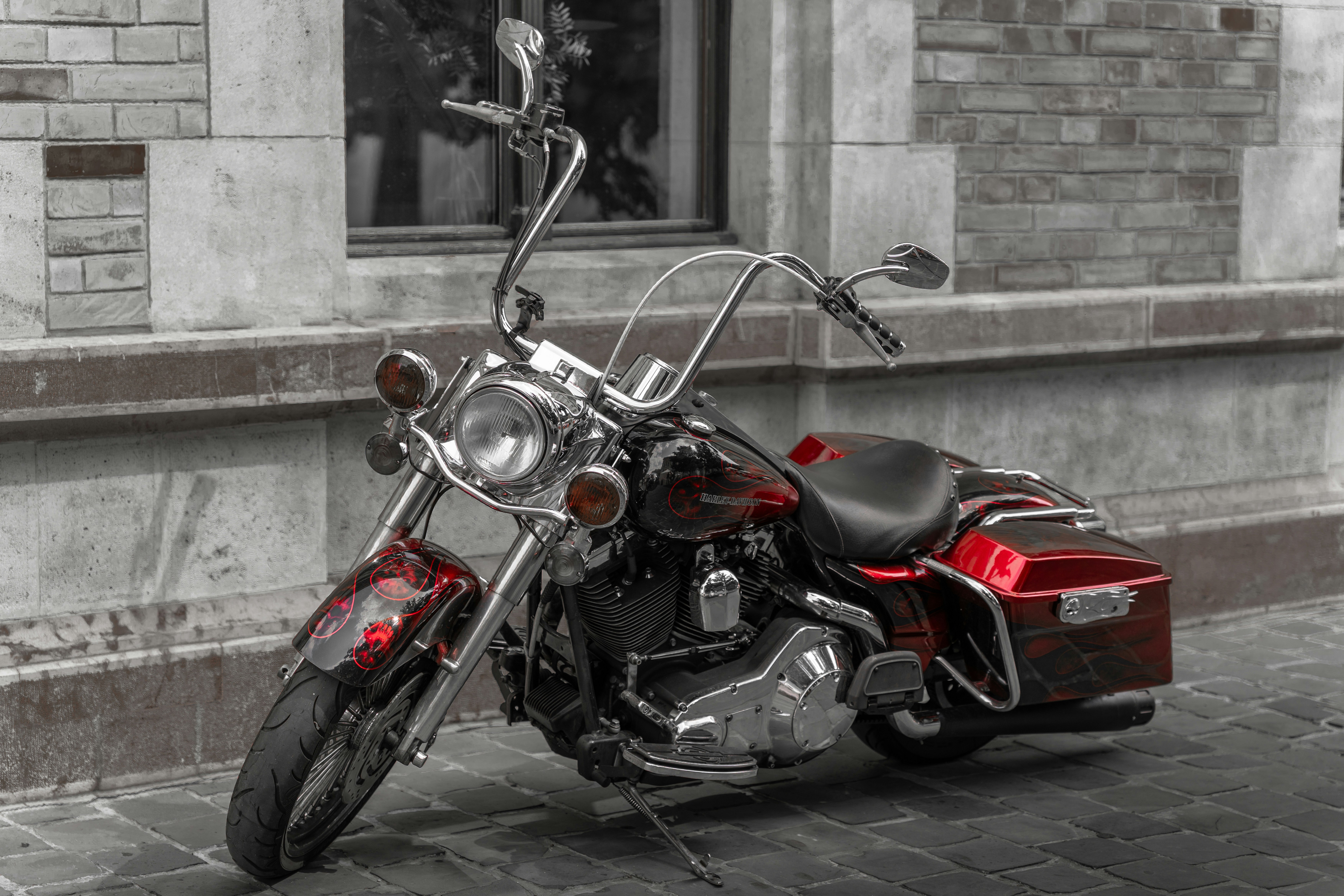 A red motorcycle parked against a stone wall.