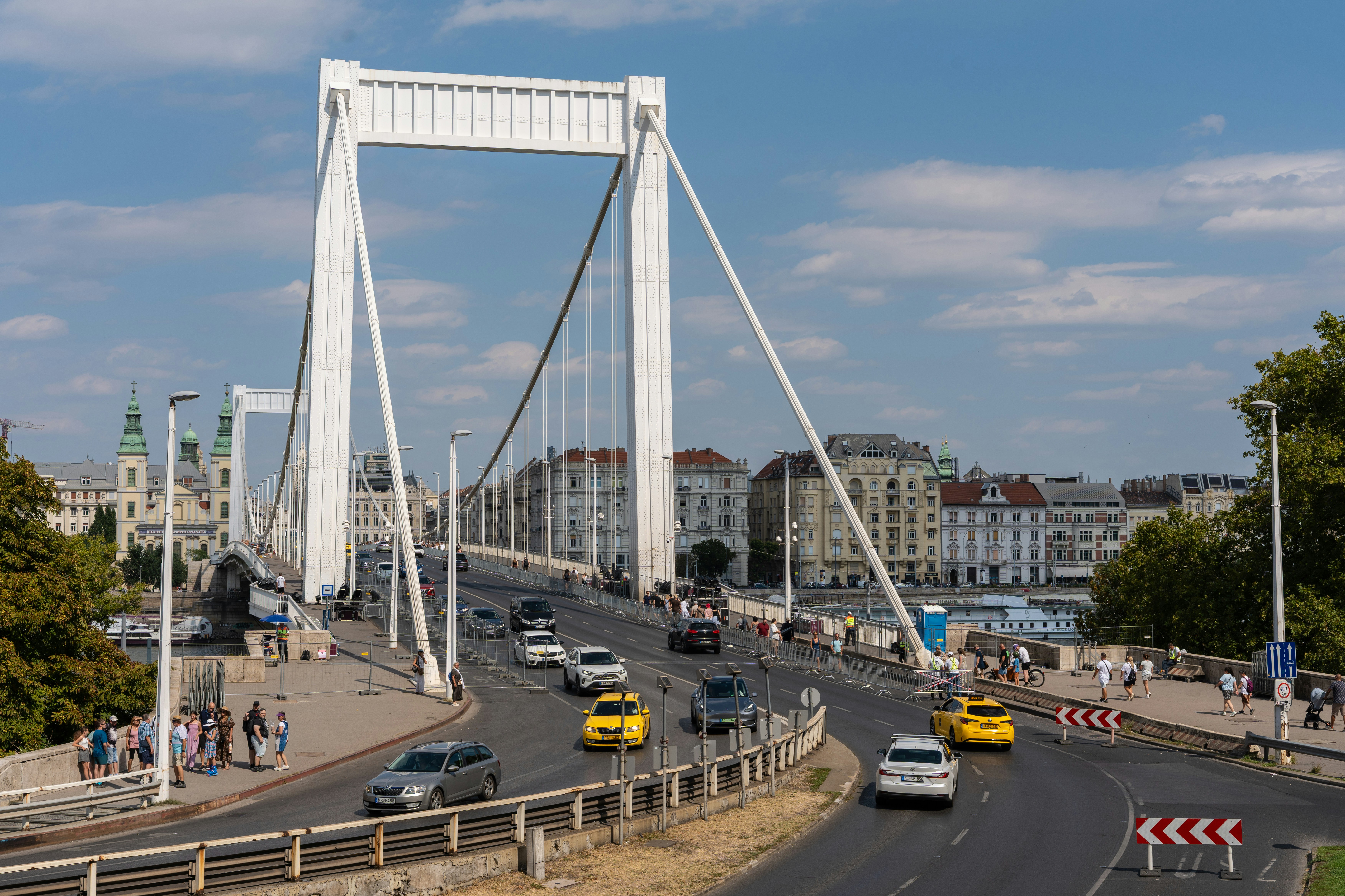 White suspension bridge with traffic and buildings