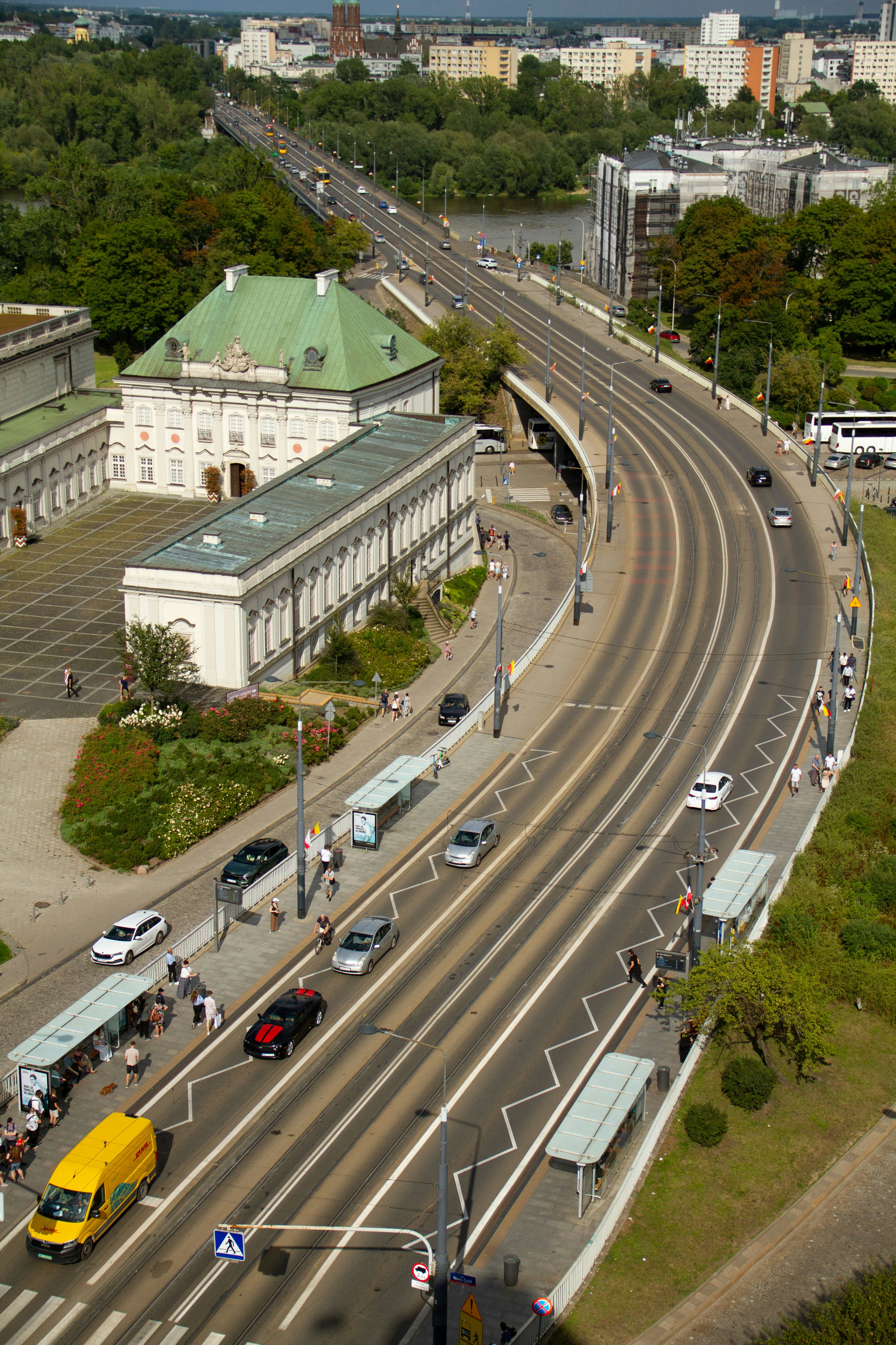 Busy city street with cars and buses near buildings.