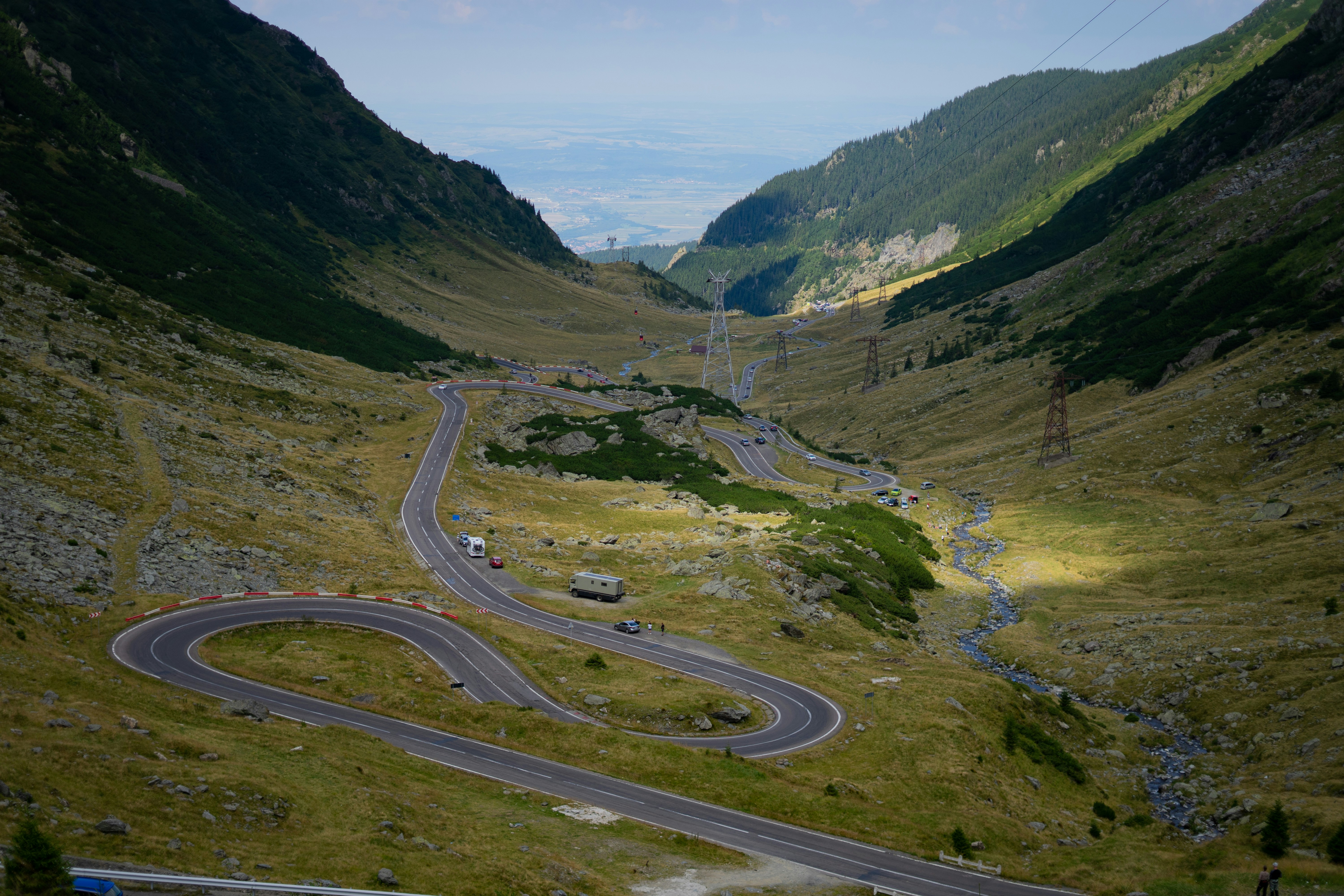 Winding mountain road with cars in a valley.