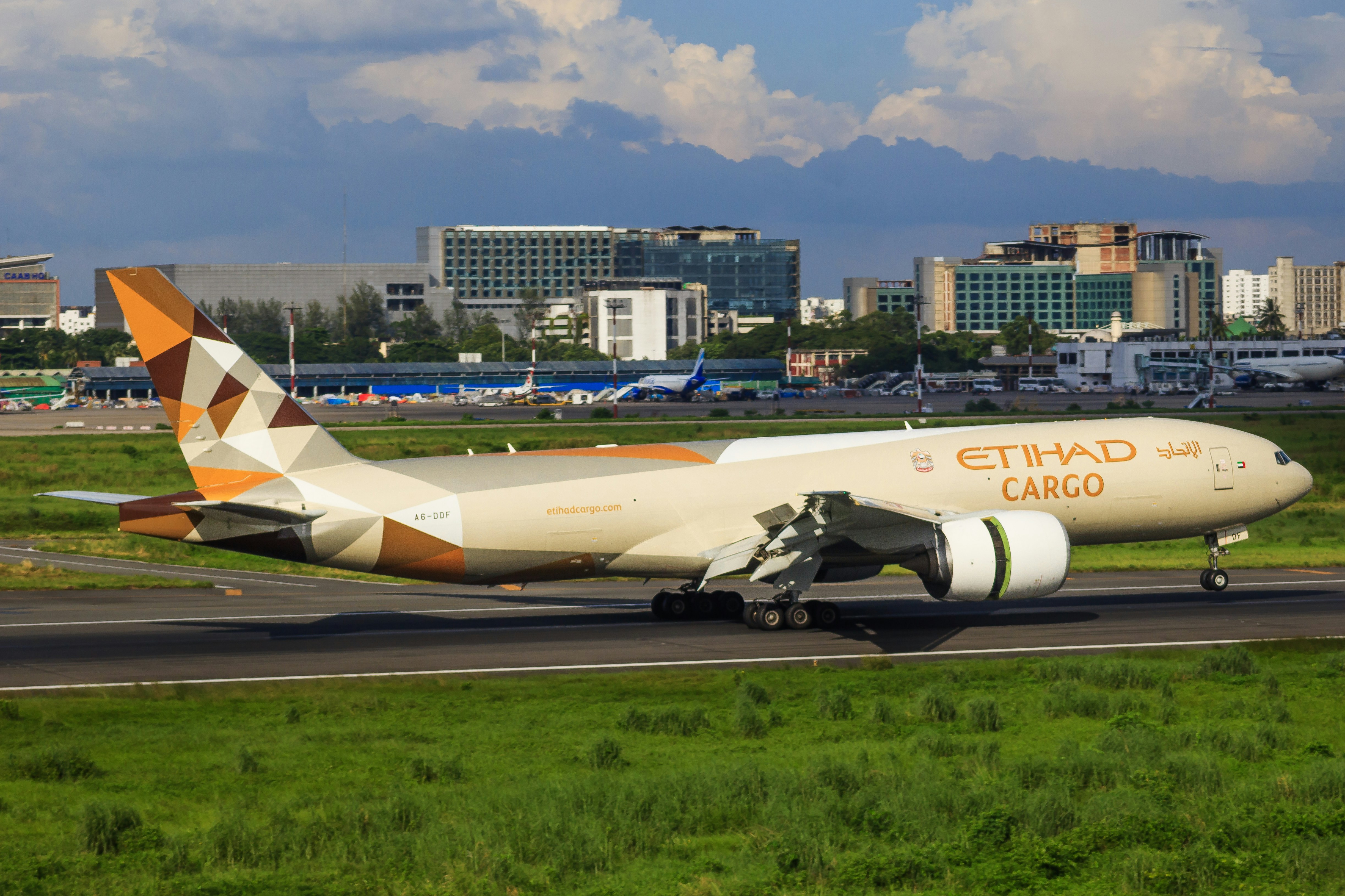 Etihad Cargo Boeing 777(F) braking at Dhaka. | Etihad cargo airplane taxiing on runway with cityscape background