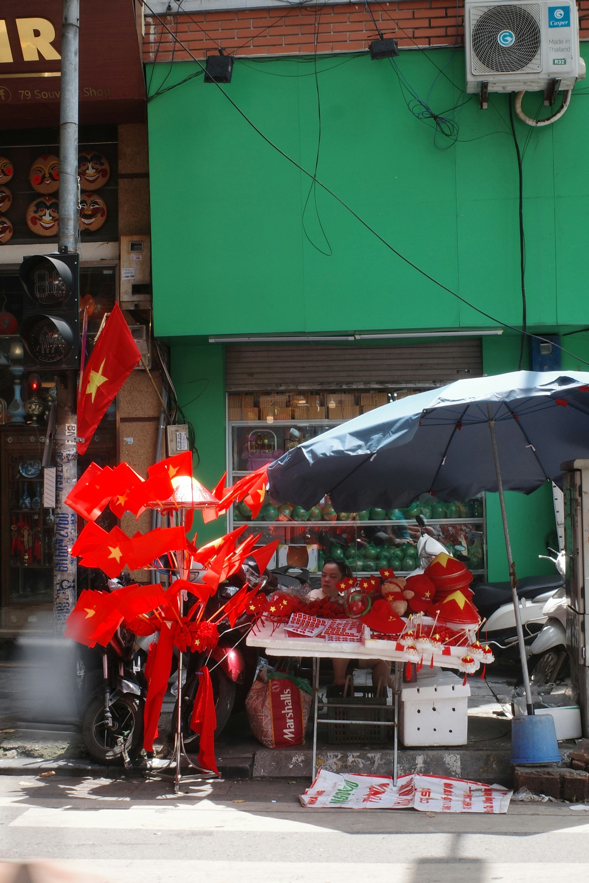 Stalls adorned with red flags and festive decorations in a bustling street market, showcasing local culture and commerce.