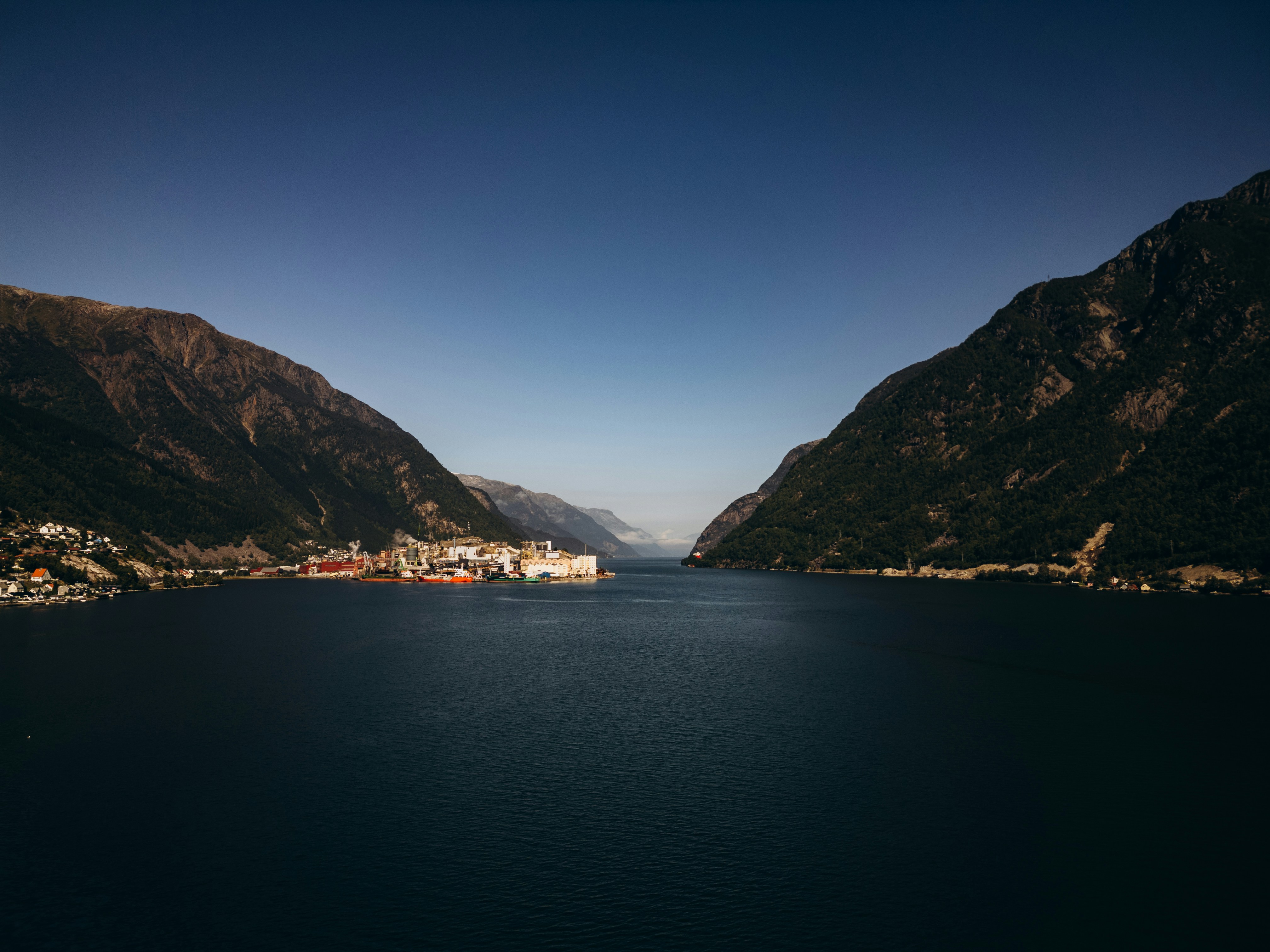 A tranquil fjord bordered by towering mountains, showcasing a small town nestled along the water's edge.