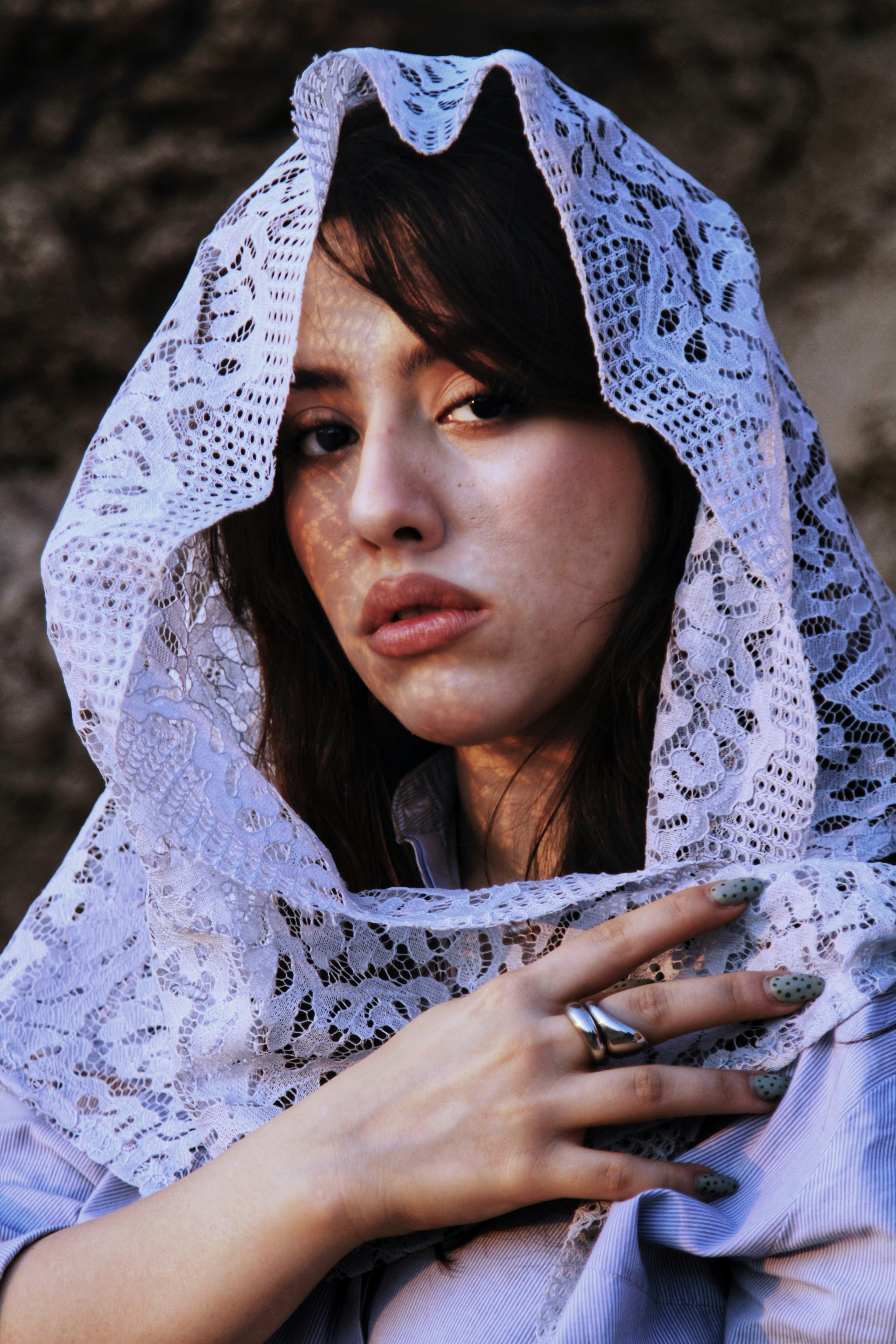 Woman wearing a white lace headscarf and silver ring.