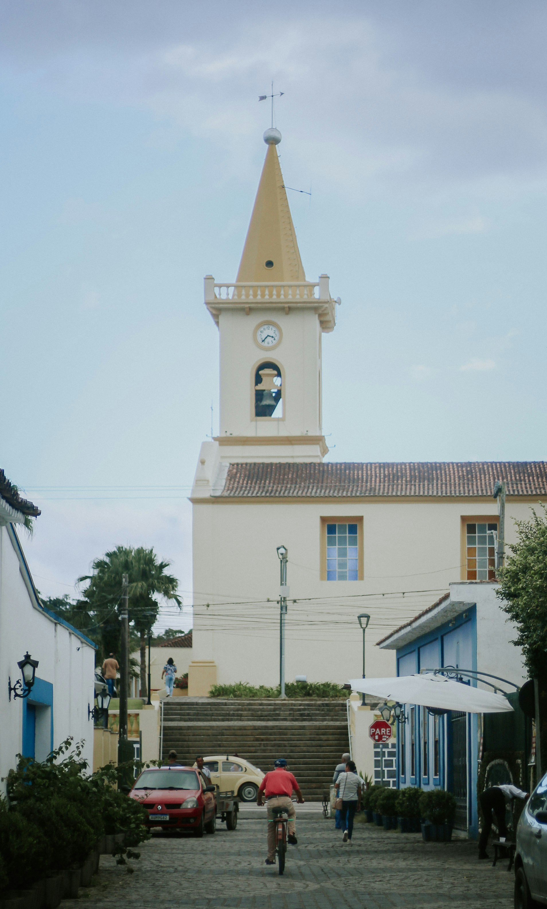 People cycling on a street with a church tower.
