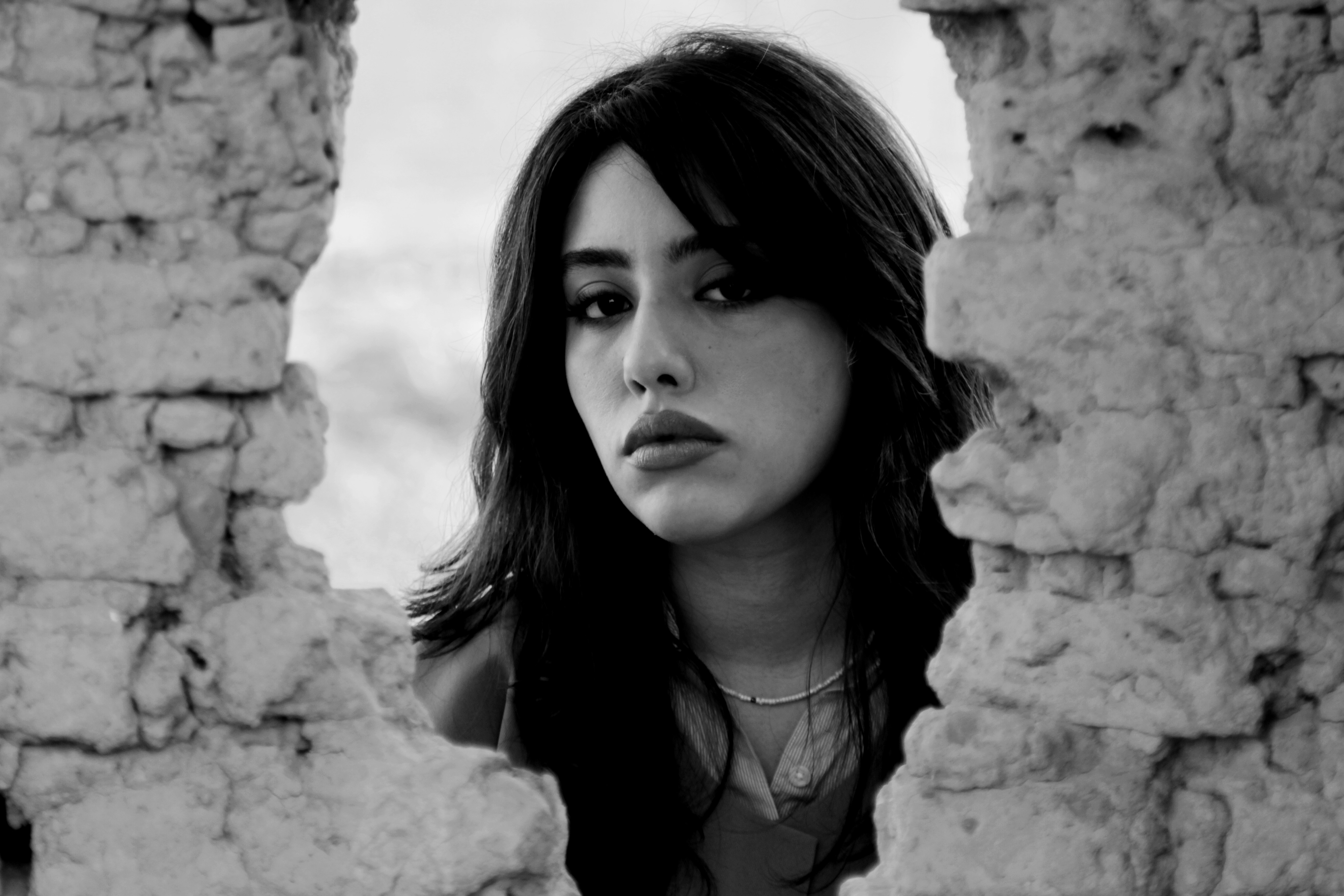 Young woman looking through weathered stone opening