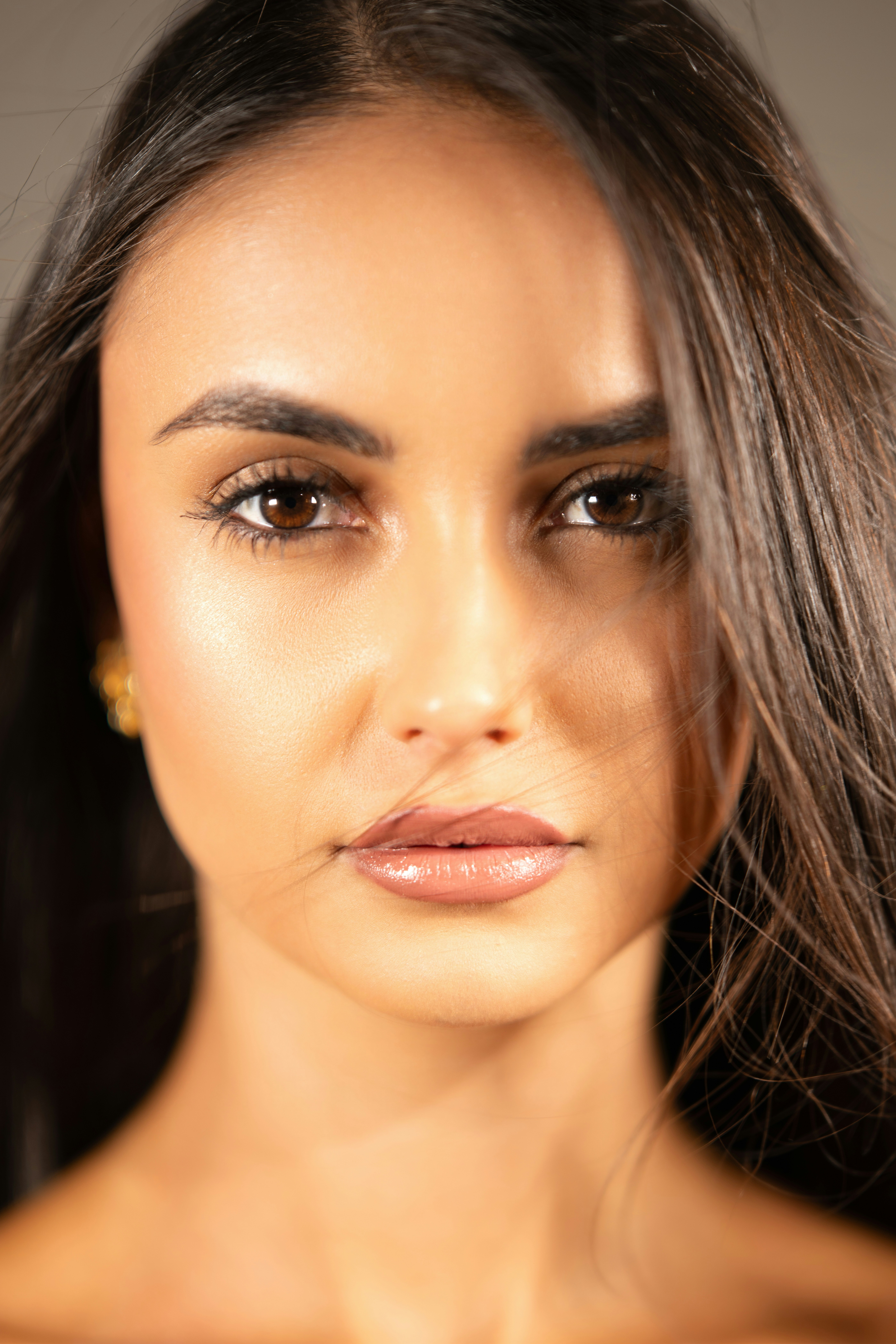 Close-up portrait highlighting the subject's expressive features and soft, flowing hair. The warm light accentuates her natural beauty.