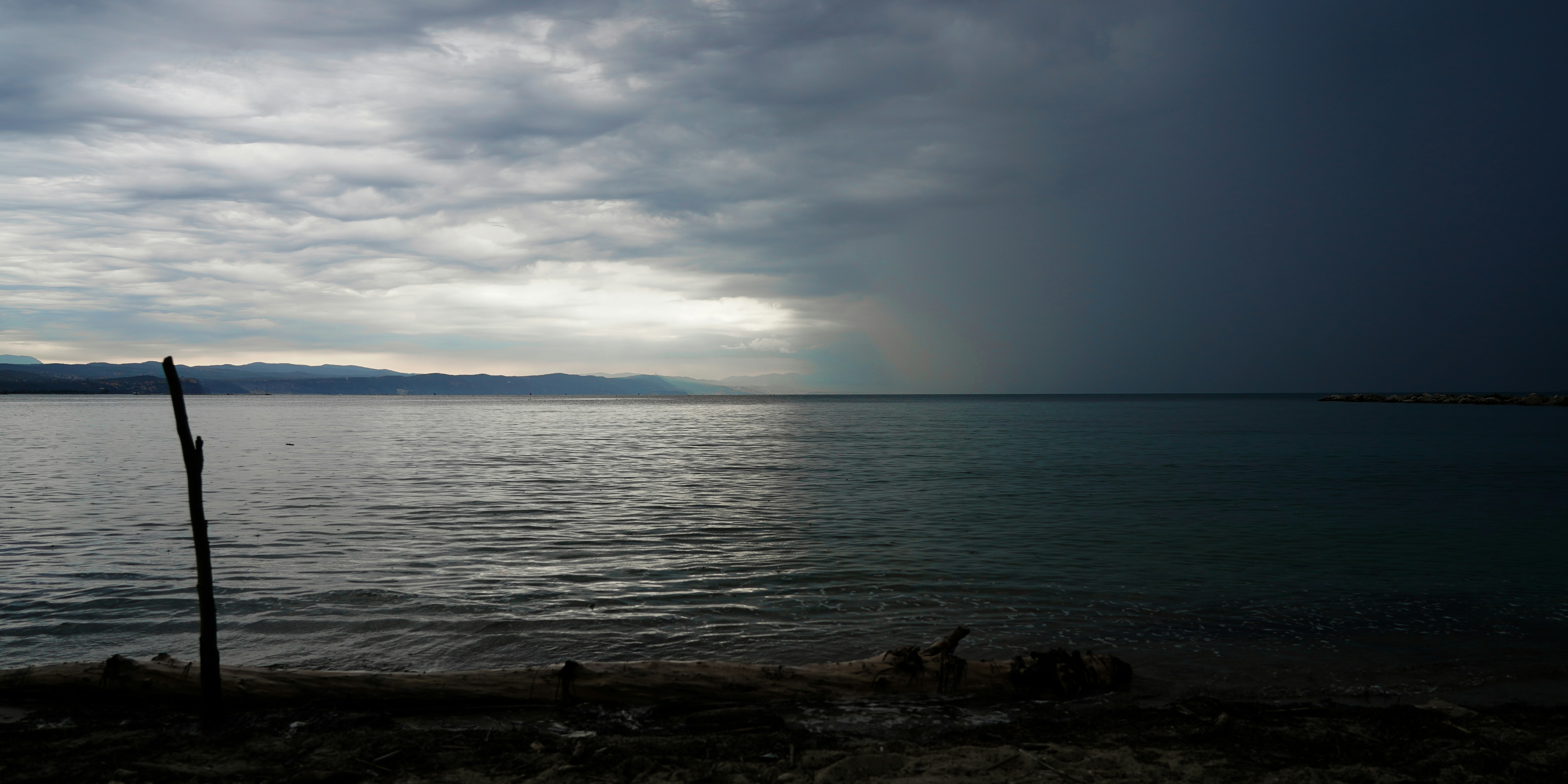 Stormy sky over a calm lake with distant mountains