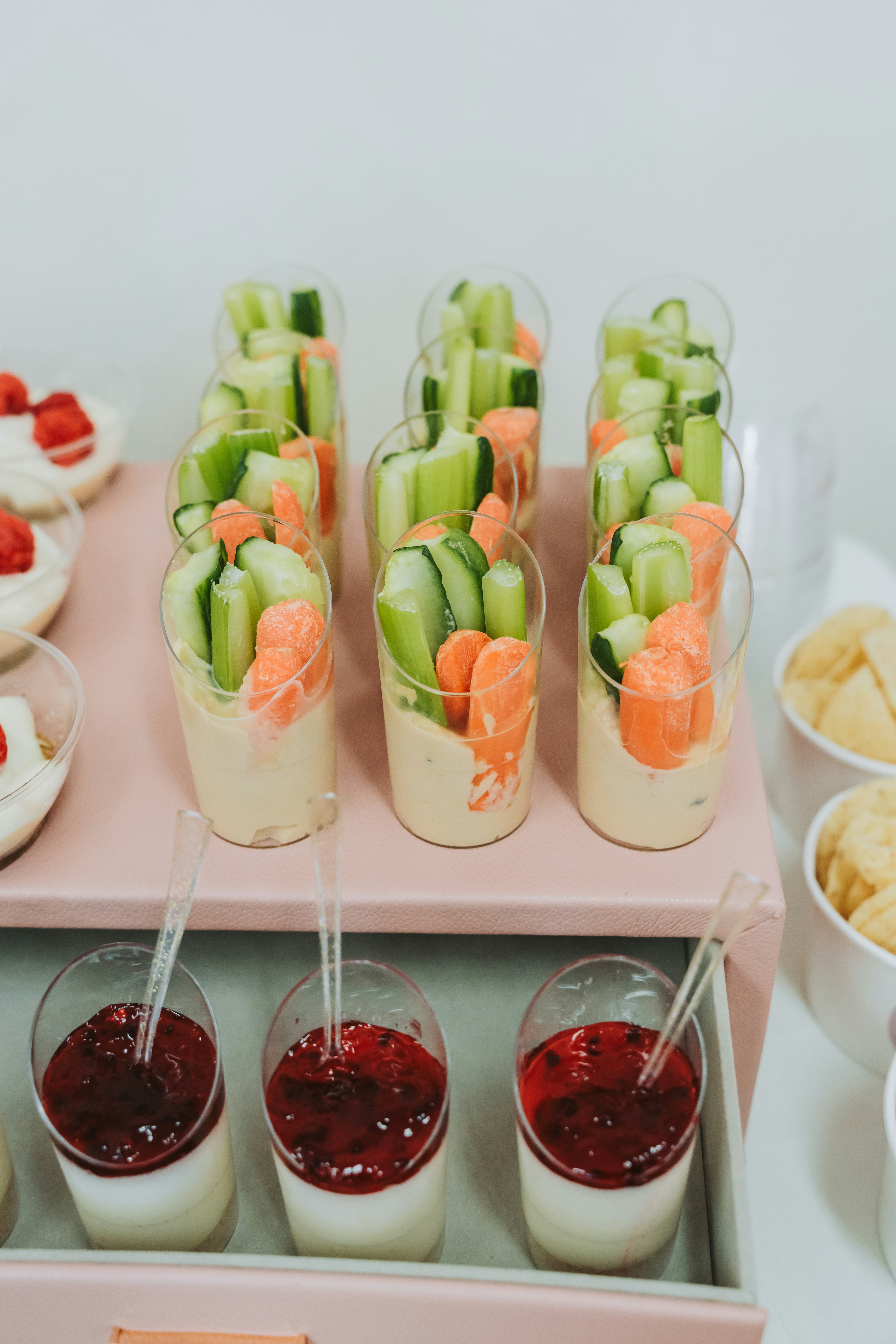 Vibrant cups filled with fresh vegetables and creamy dip, alongside dessert cups topped with berry compote. Perfect for a festive gathering.