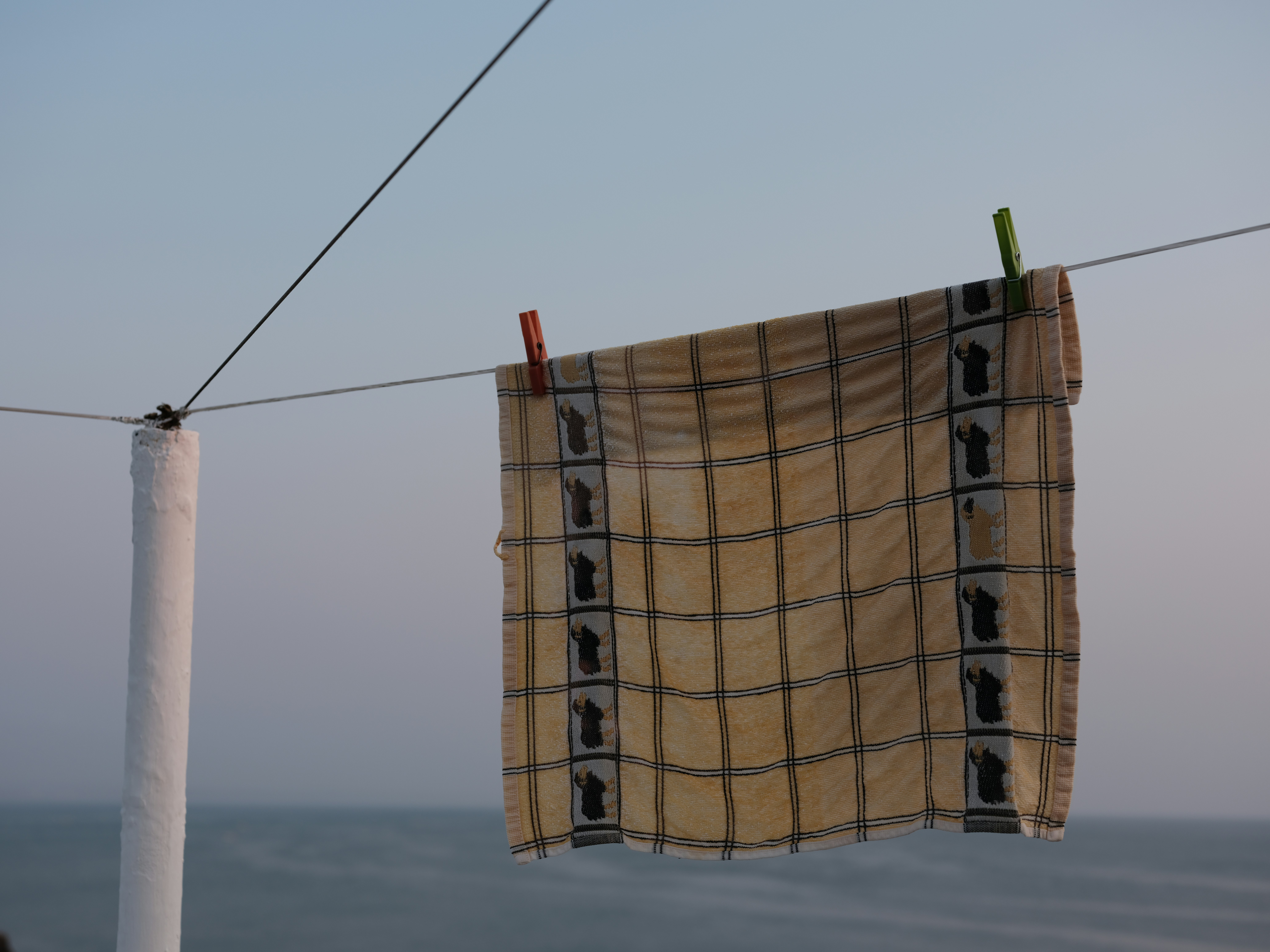 Gridwork on the Line: A Linen Cloth Framed by Sea and Sky.