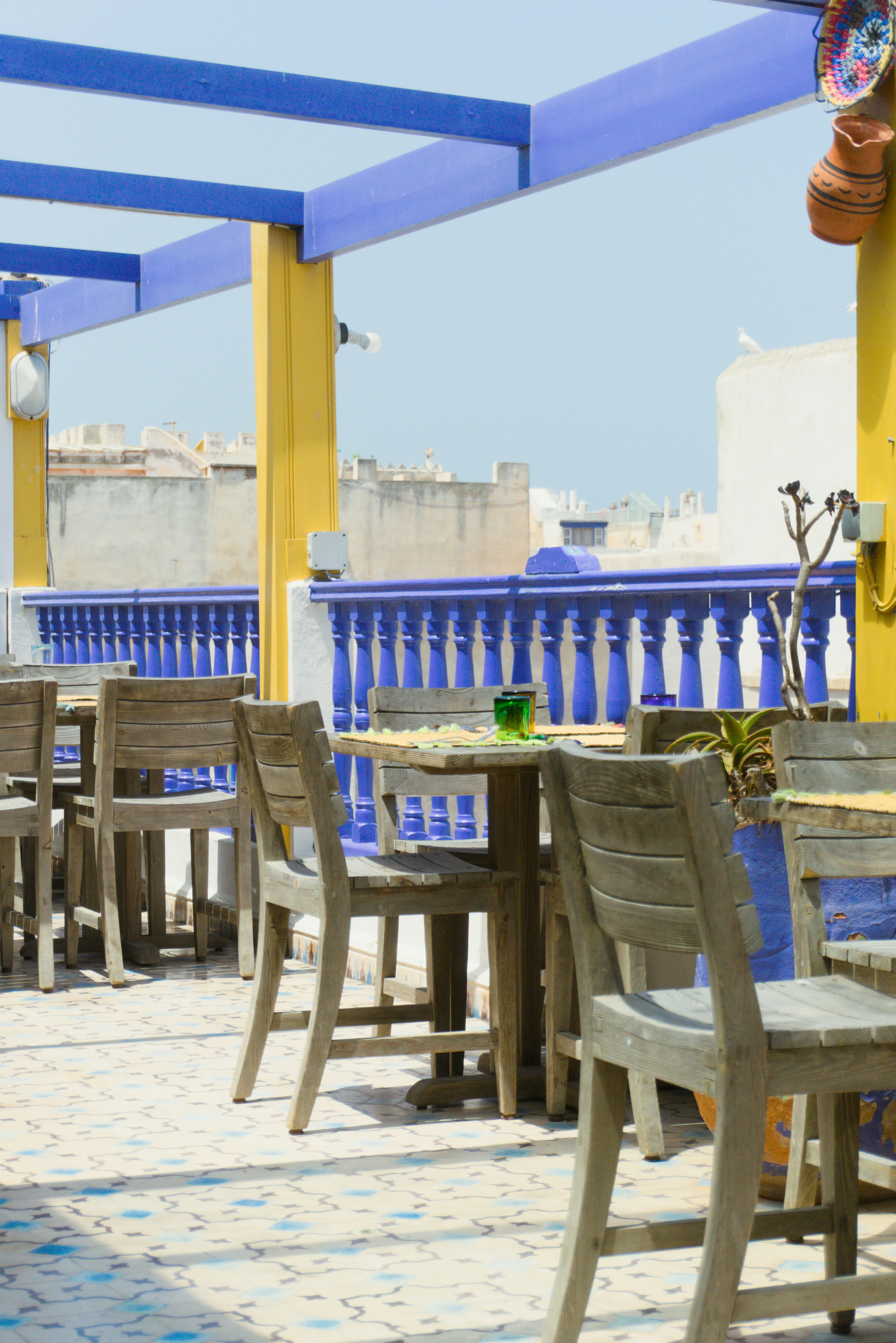 The patio of a restaurant in Essaouira. | Outdoor cafe seating with blue and yellow accents