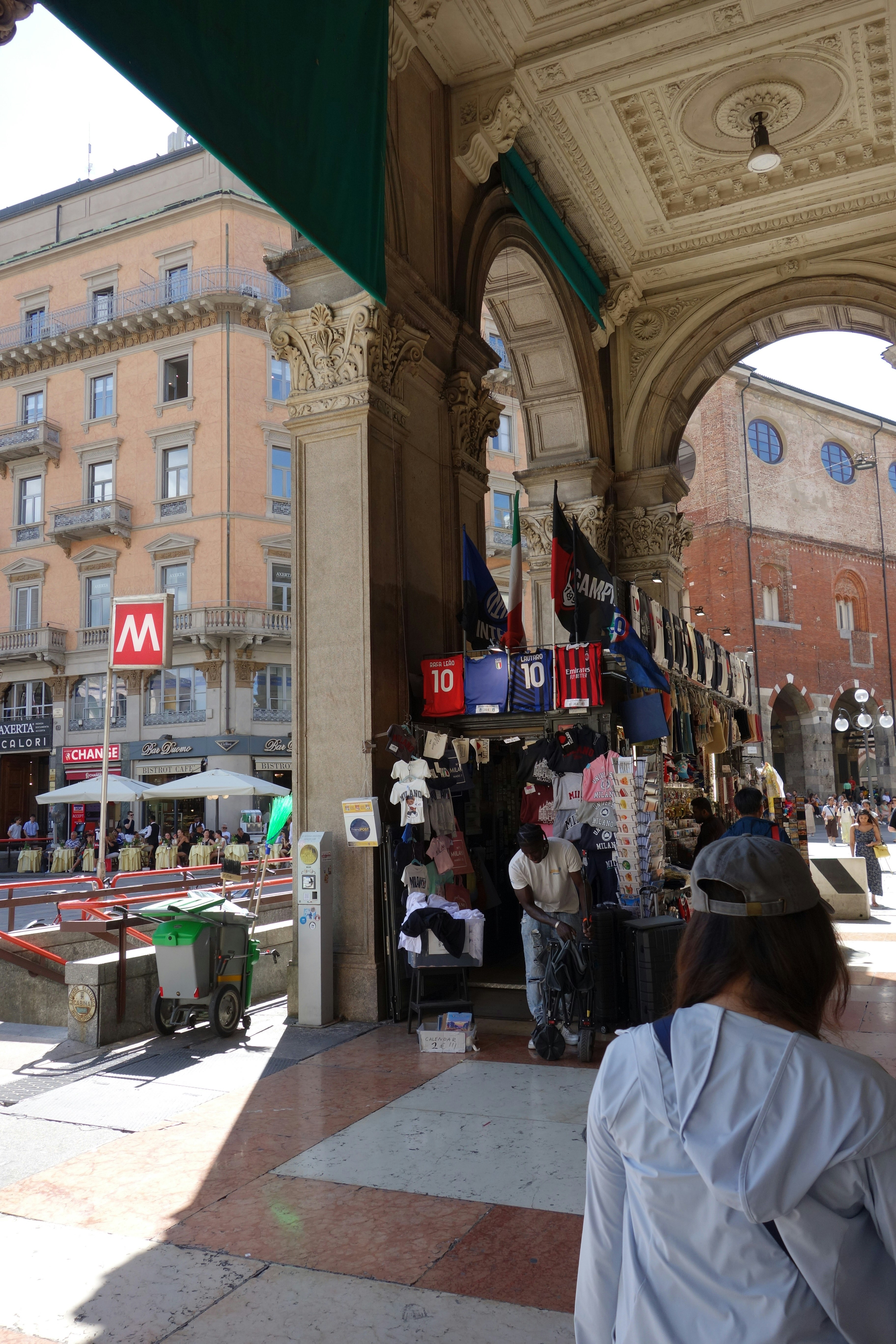 People browse souvenirs under ornate arched arcade.