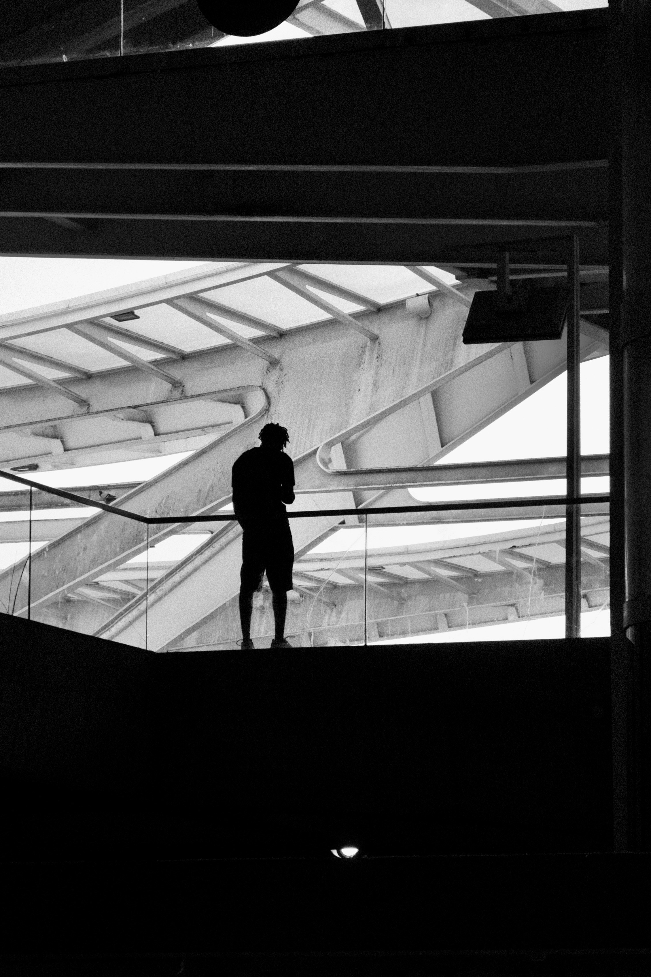 Silhouette of a person standing on a balcony looking out.