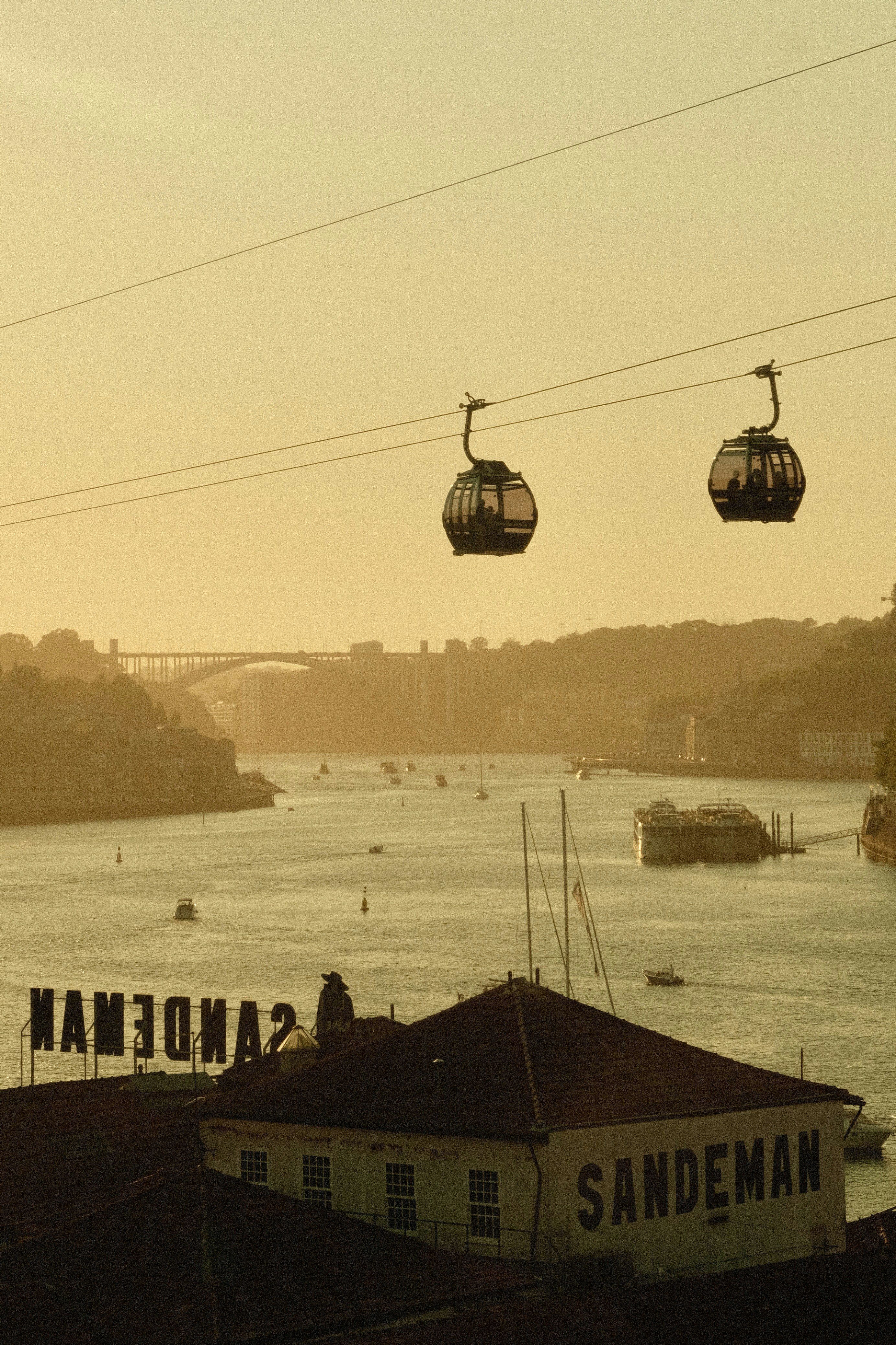 Cable cars crossing river at sunset with boats.